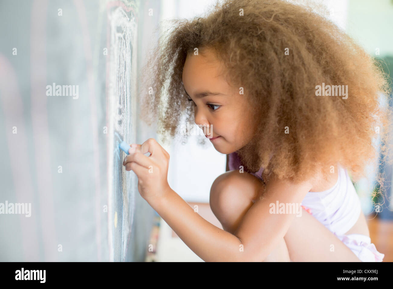 Mixed race girl writing on blackboard Stock Photo - Alamy