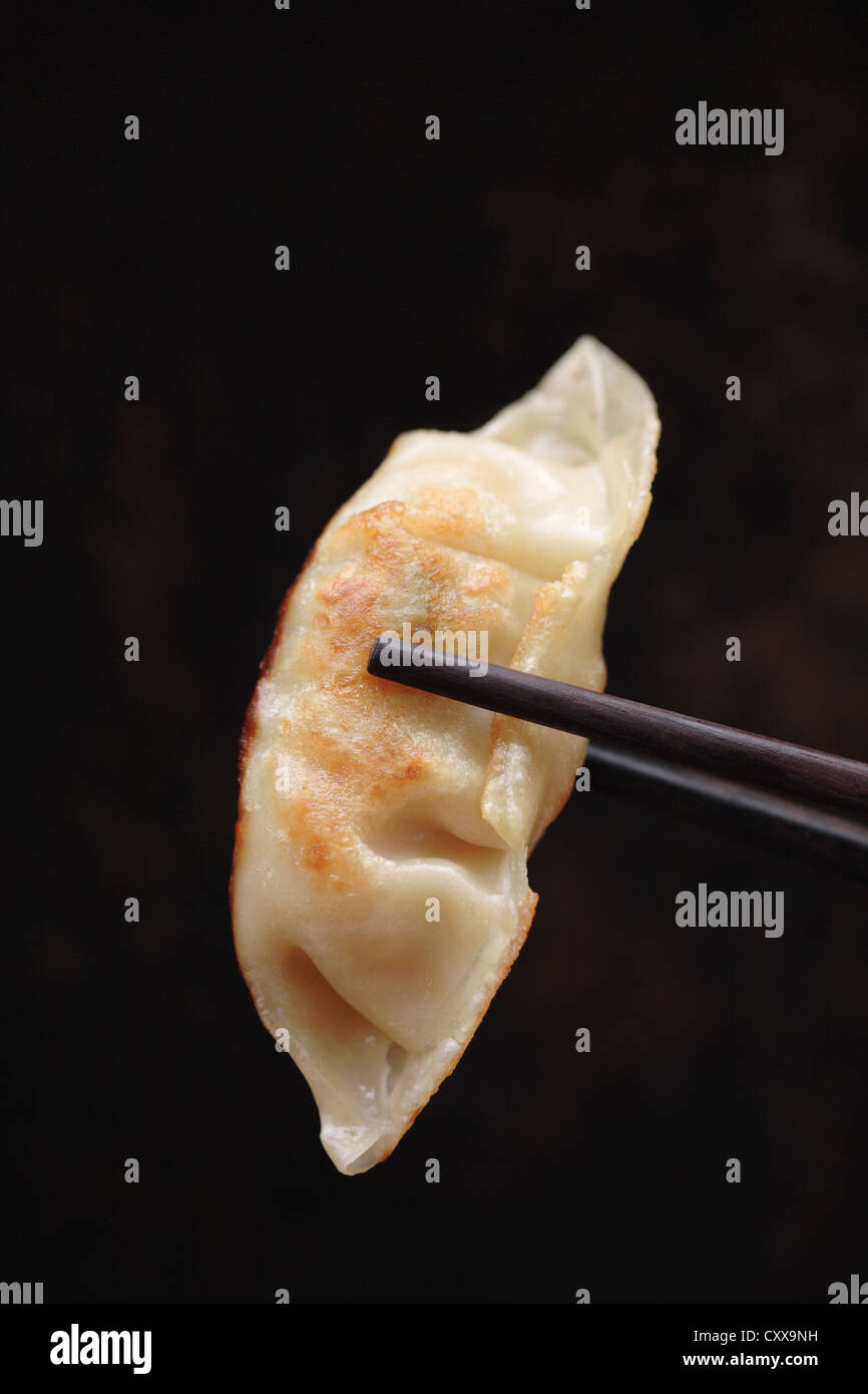 Chopsticks holding Asian dumpling Stock Photo - Alamy