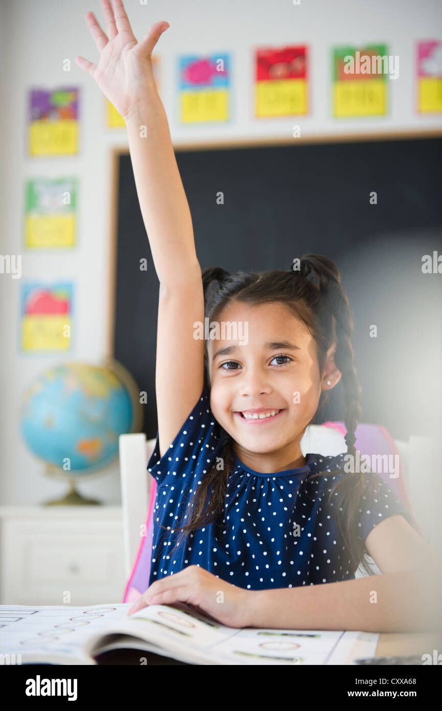 Mixed race girl raising her hand in classroom Stock Photo - Alamy