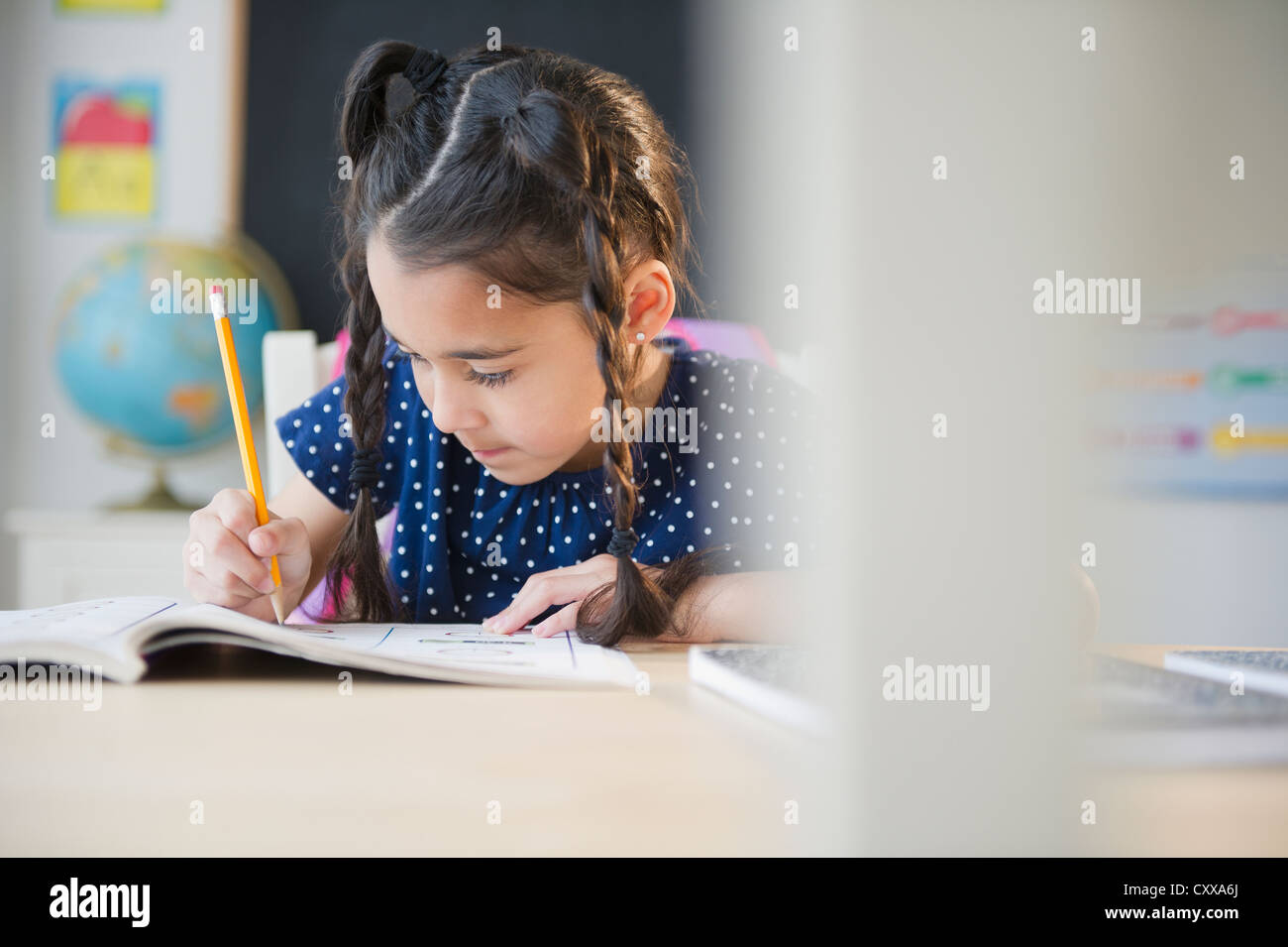 Mixed race girl writing in school Stock Photo - Alamy