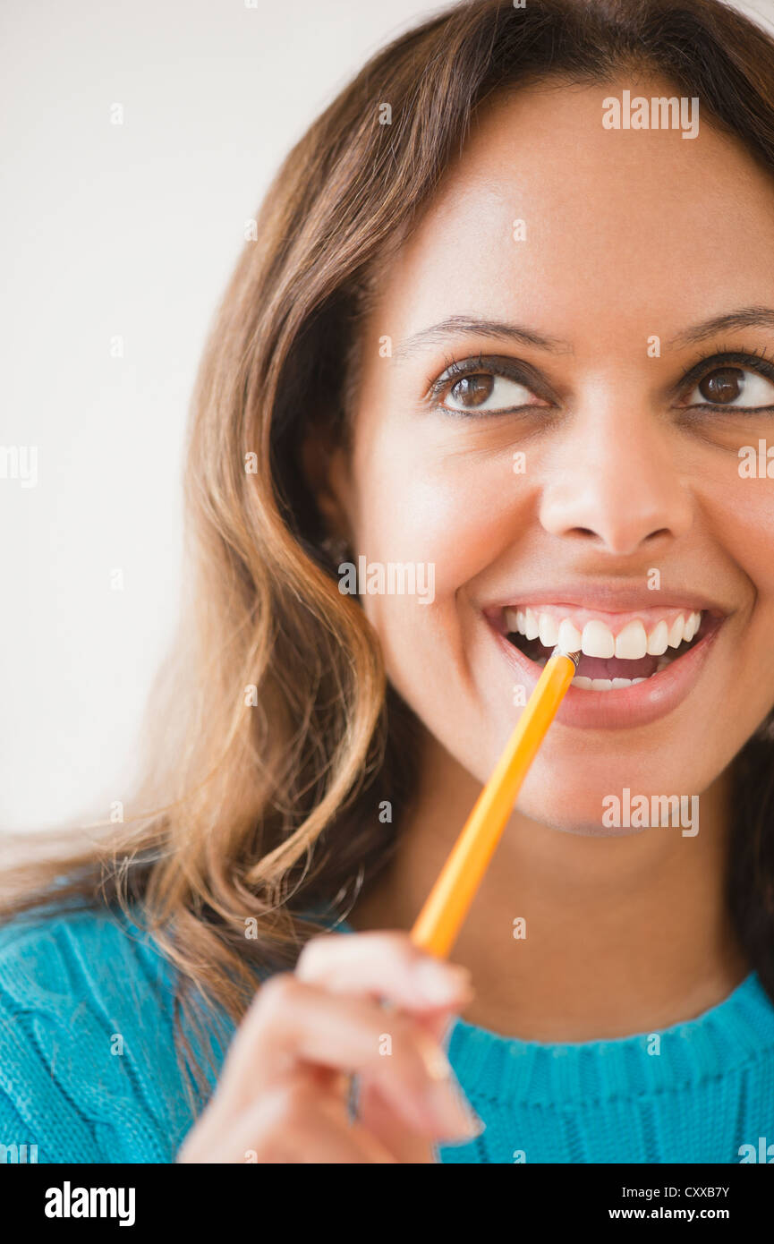 Cape Verdean woman biting pencil Stock Photo - Alamy