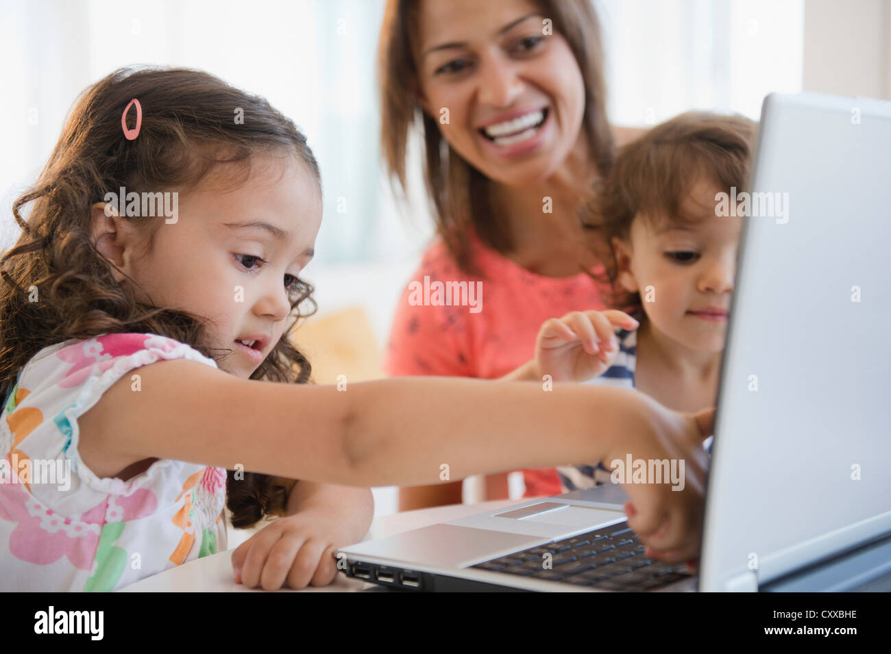 Mother watching children using laptop Stock Photo - Alamy