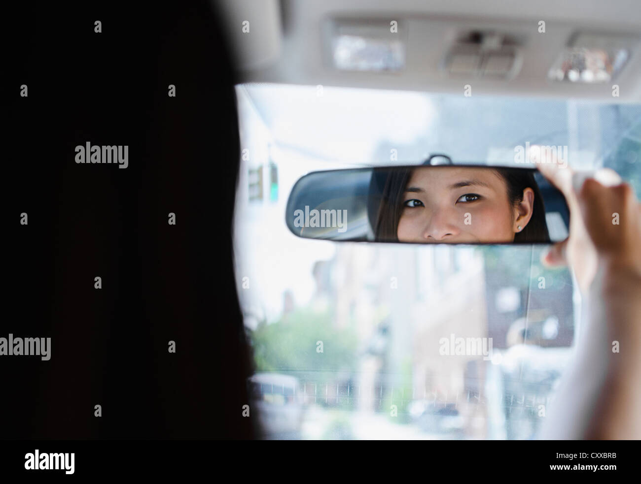Asian woman adjusting rear-view mirror Stock Photo - Alamy