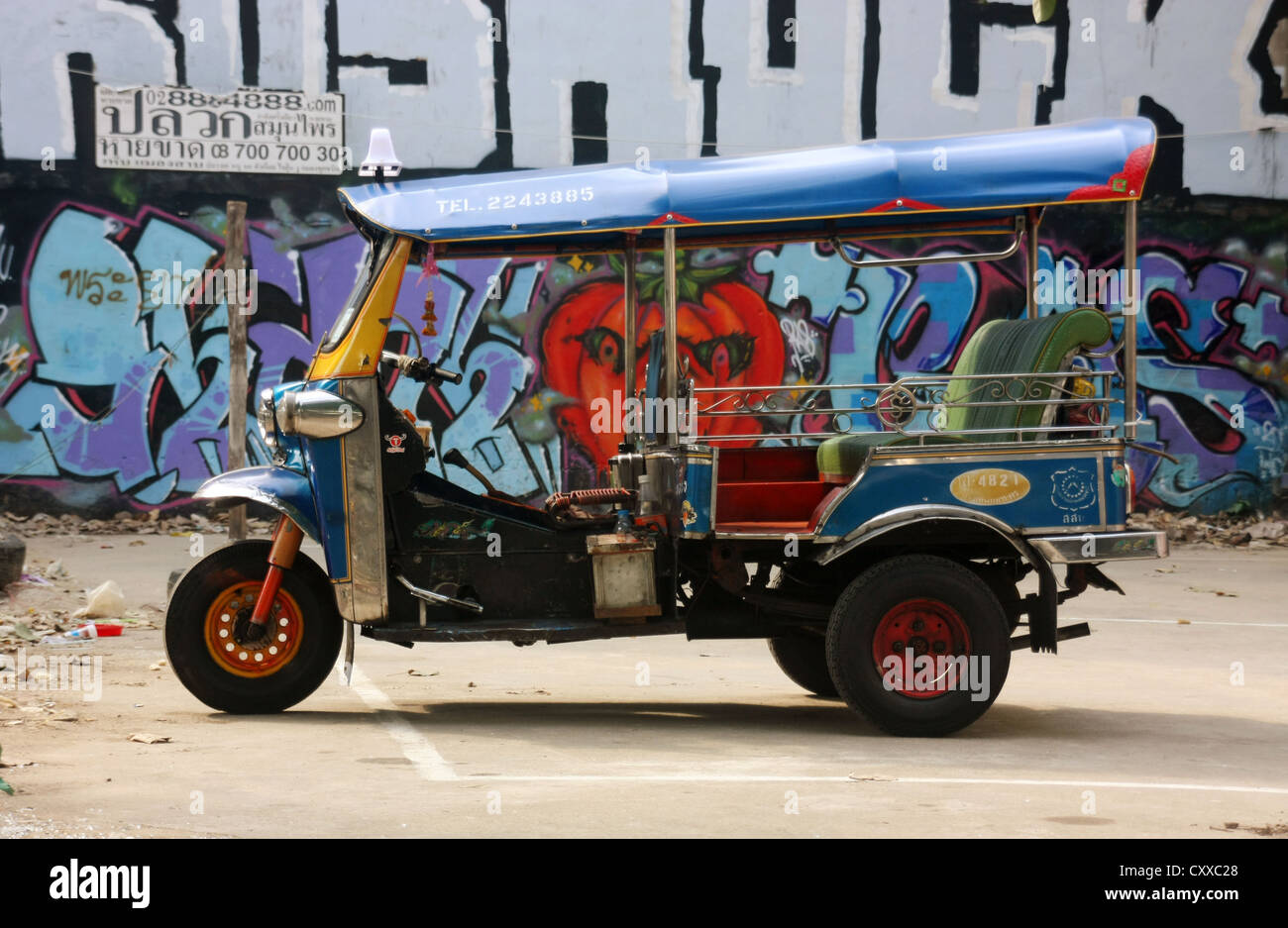 Tricycle motor rickshaw taxi in front of graffiti wall Bangkok ...