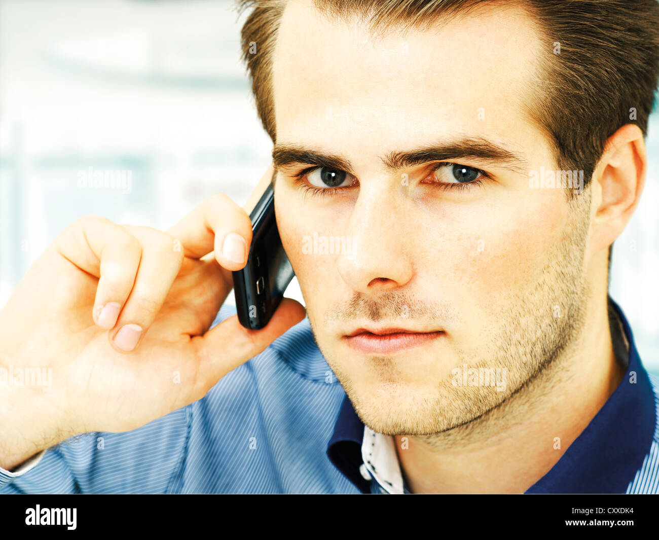 Young man speaking on his mobile phone, serious face Stock Photo - Alamy