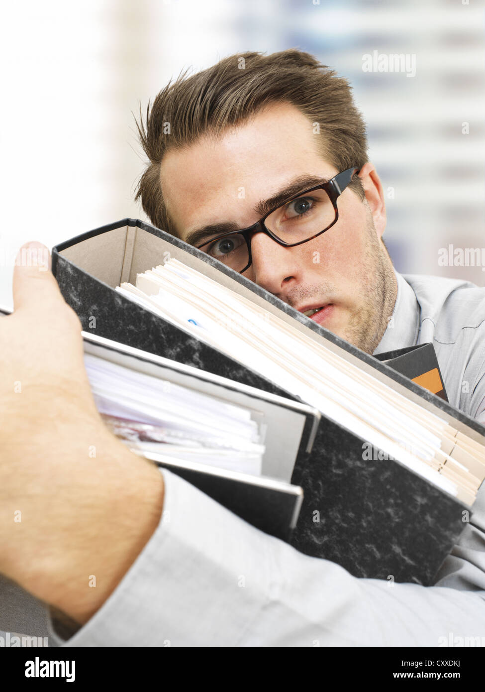 Stressed young businessman wearing glasses carrying document files ...