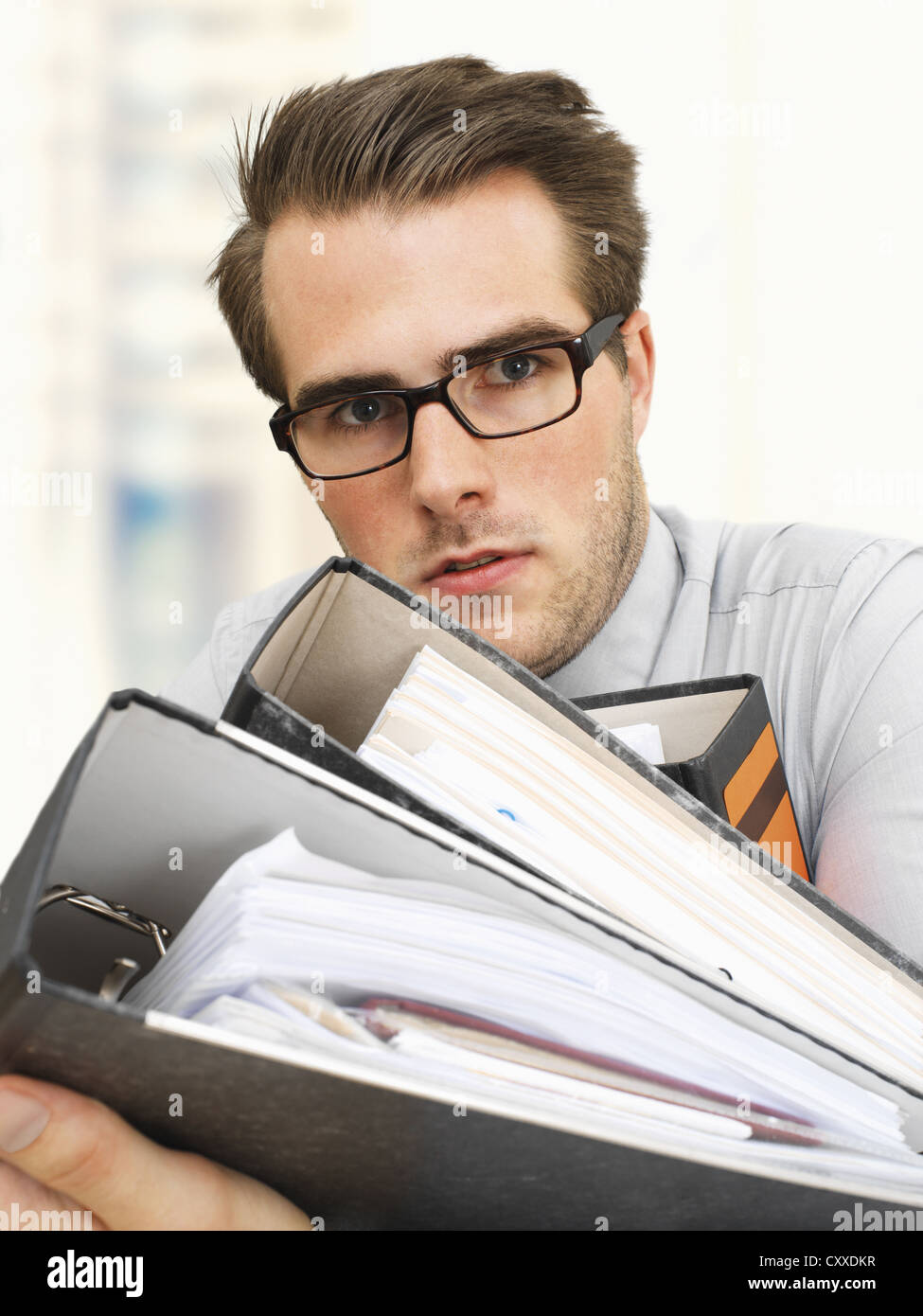 Young businessman wearing glasses carrying document files, serious face ...