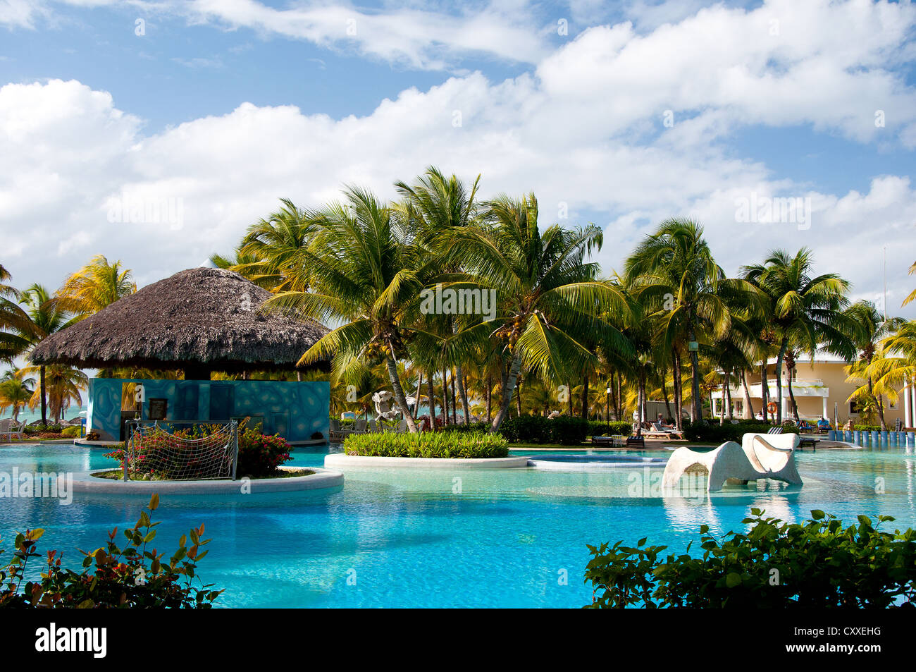 A landscaped turquoise blue resort hotel swimming pool in the tropical ...