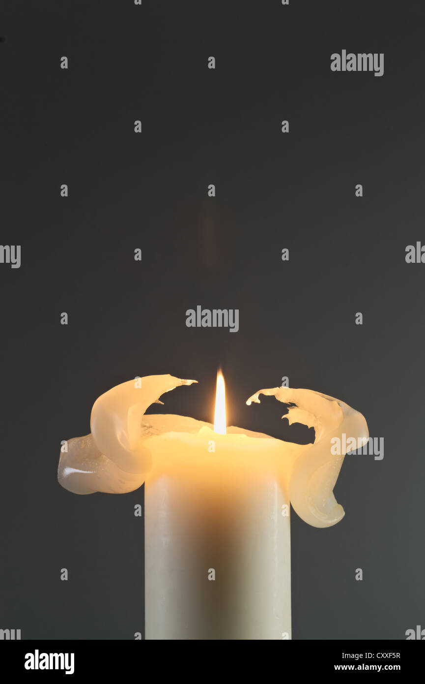 White candle burning, deformed wax Stock Photo - Alamy