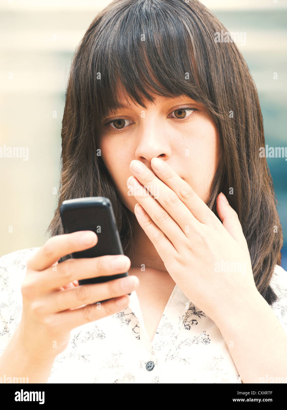 Young woman reading a text message, looking shocked Stock Photo - Alamy