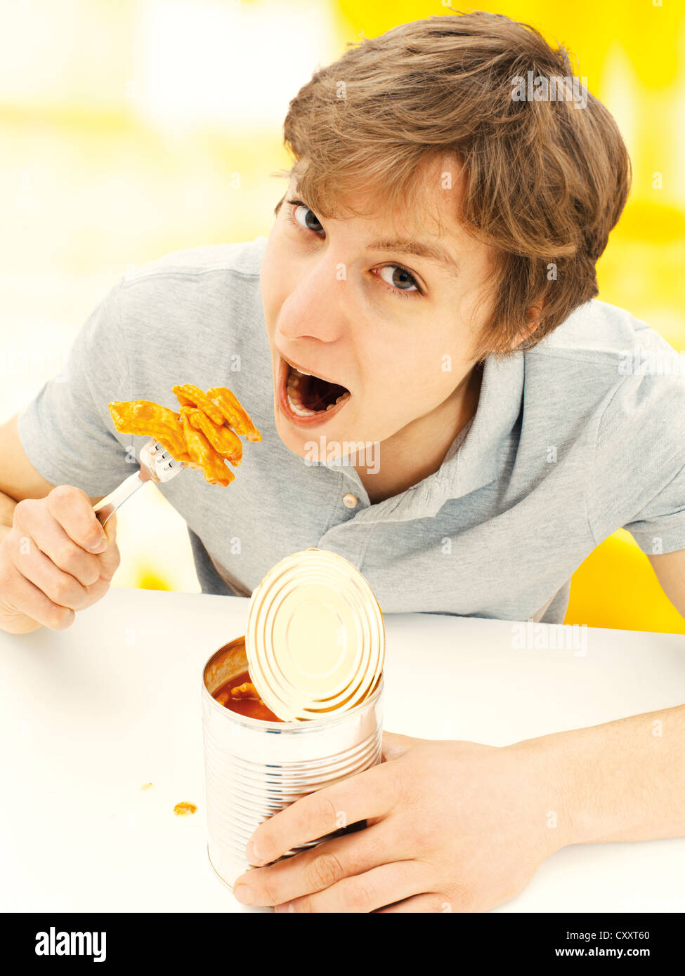 Young man eating ravioli from a tin can Stock Photo - Alamy