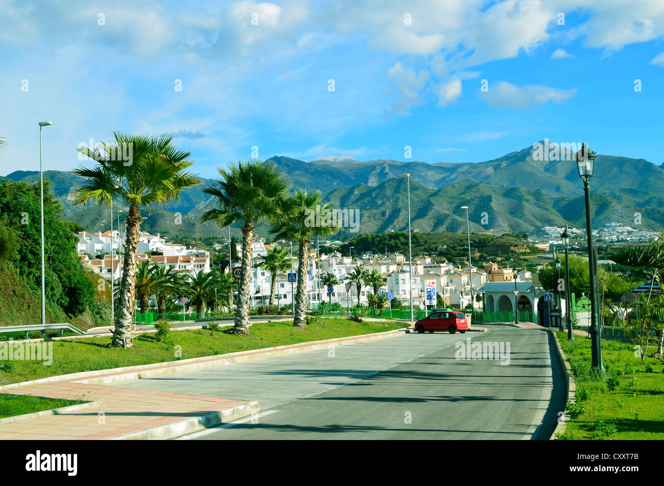 The Road into Nerja with Palm trees and white Houses with Mountains in ...