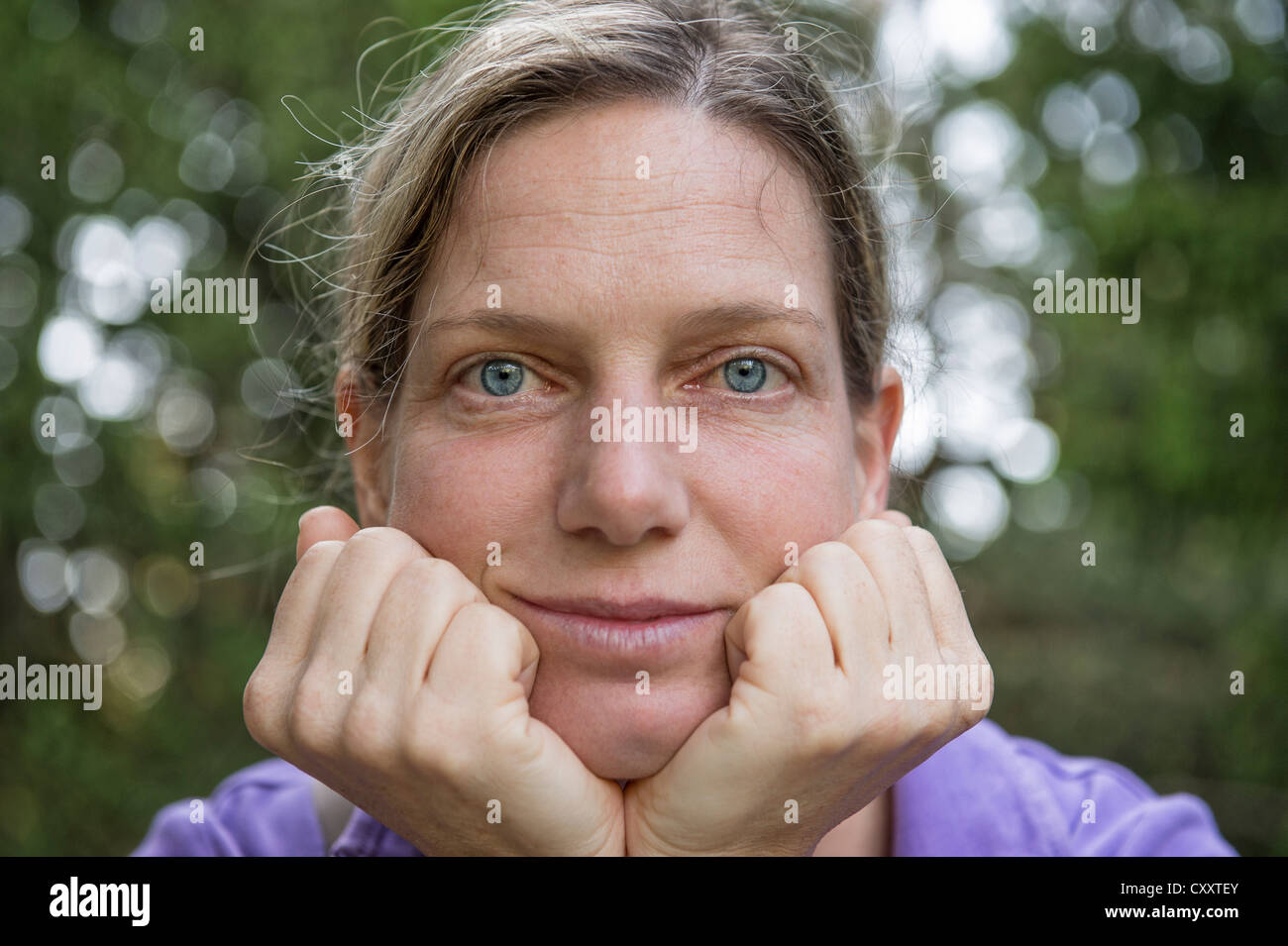 Woman, early 40's, supporting her head with her hands, looking ...