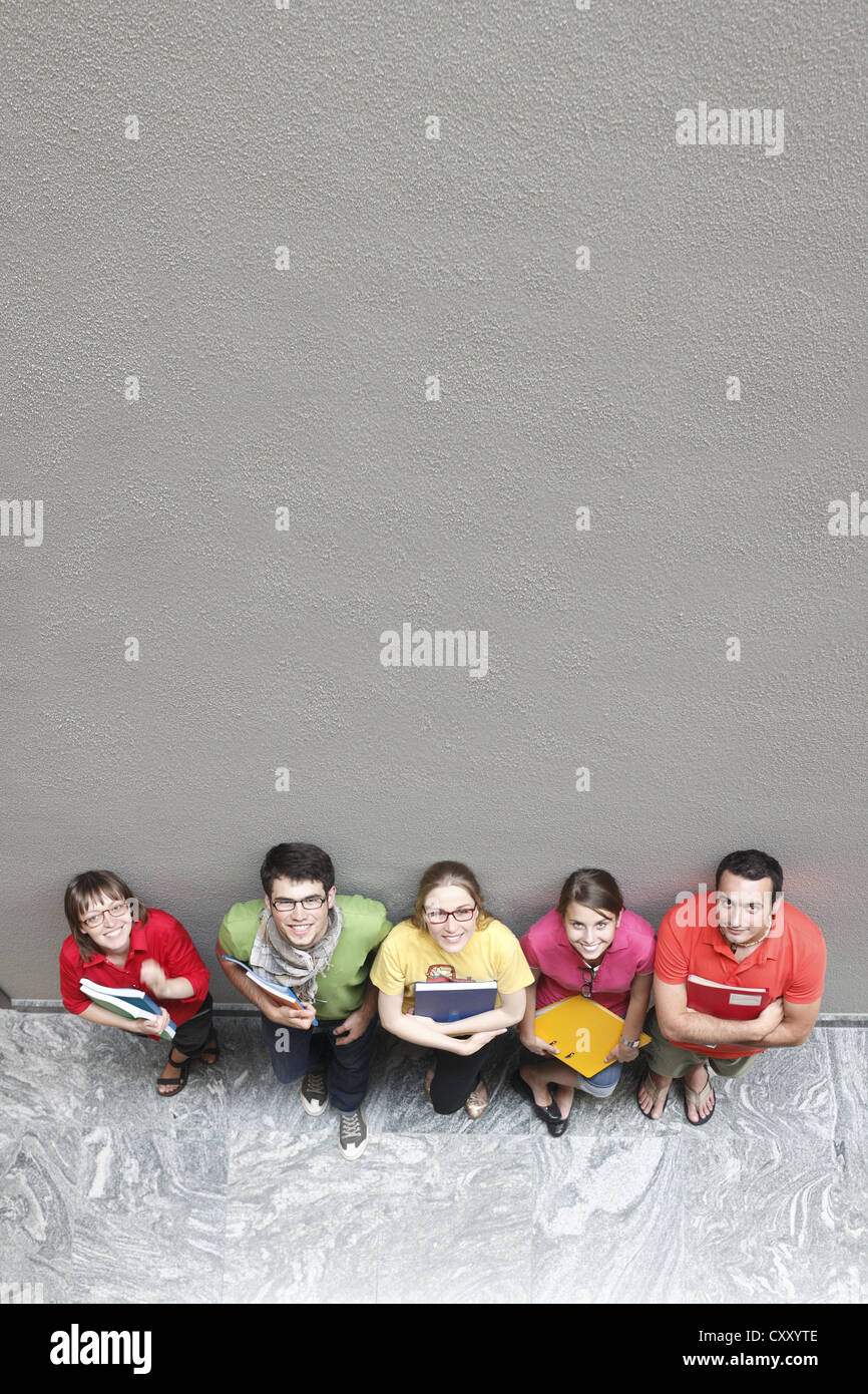 Students leaning against a wall, looking upwards Stock Photo - Alamy