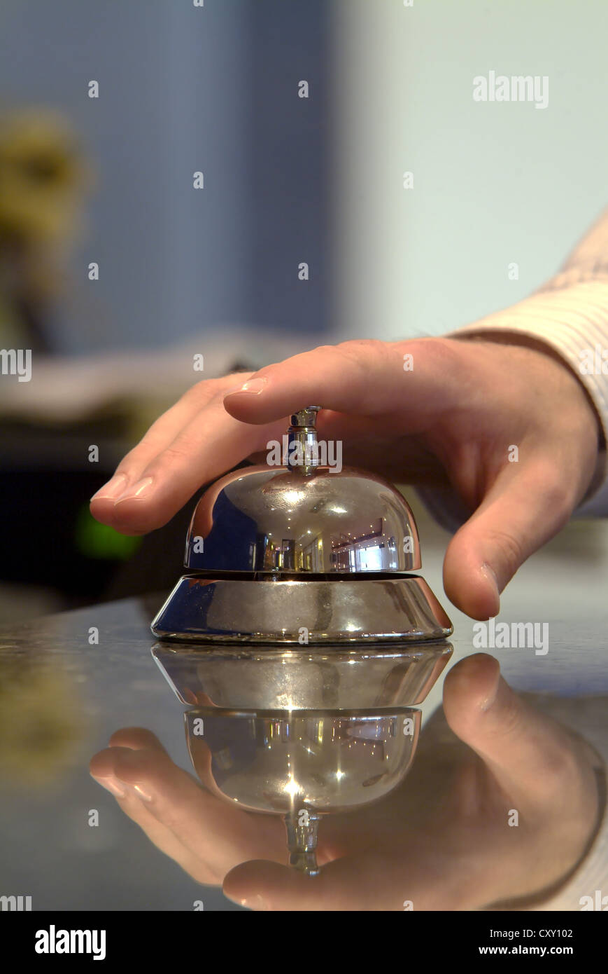 Hand resting on a hotel reception bell Stock Photo - Alamy