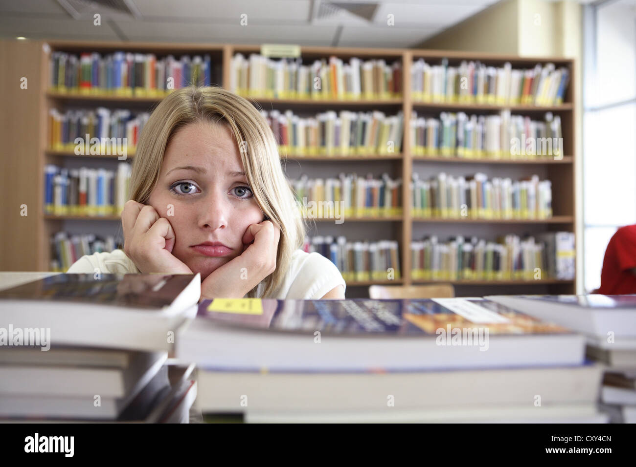 Frustrated student looking over stacks of books, university library ...