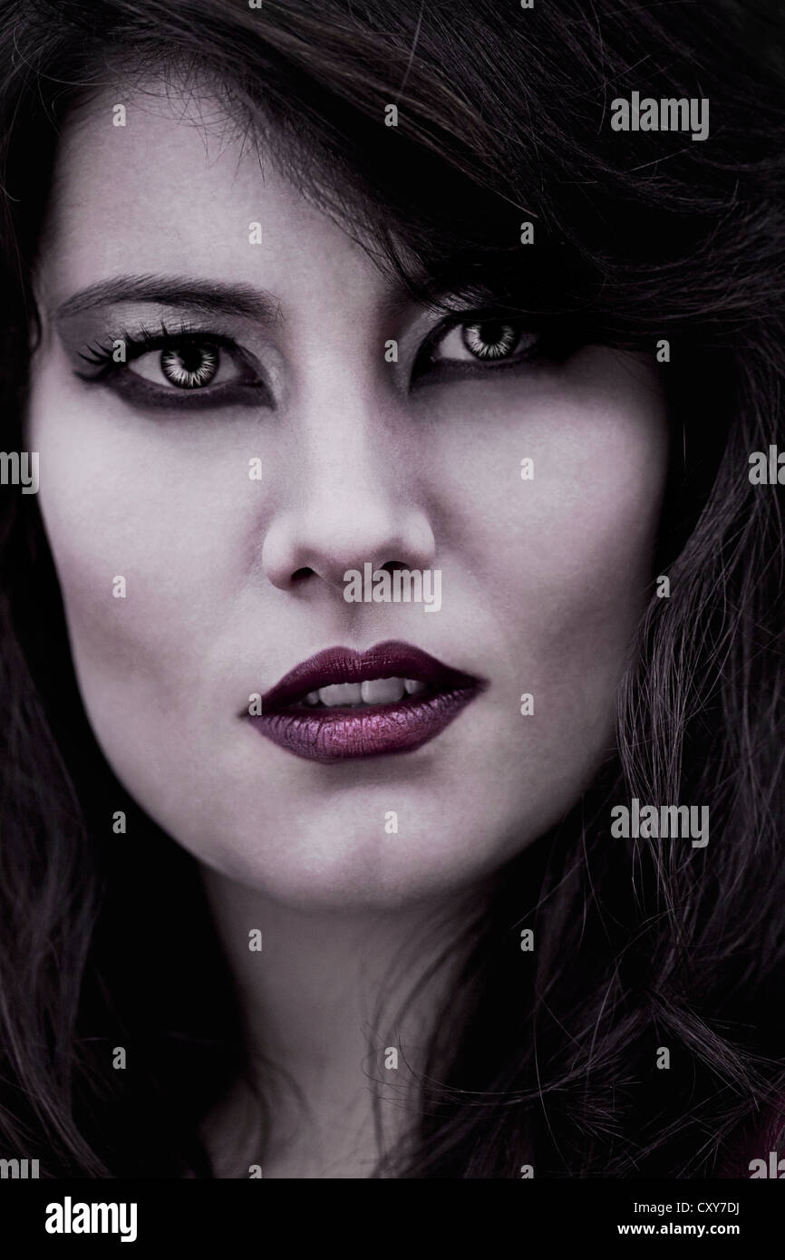 Close-up portrait of a young woman, vampire like, staring at the camera ...