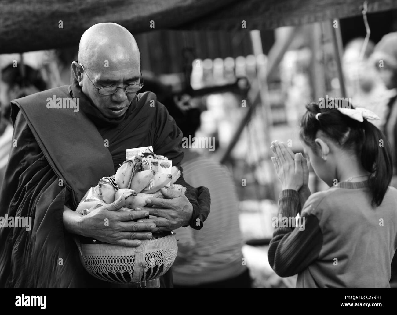 An old Buddhist monk blessing a young girl after receiving alms from ...