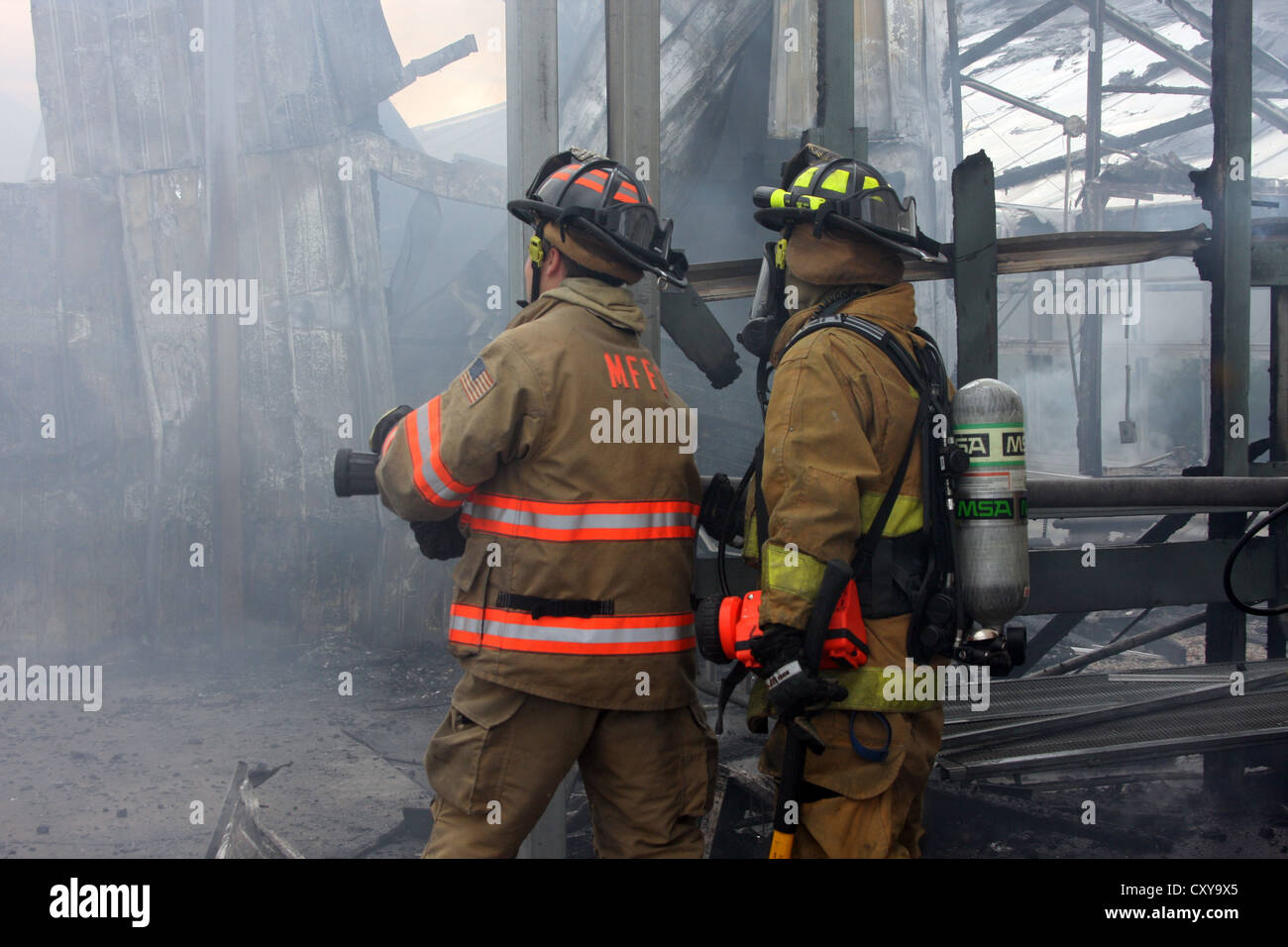 Two firefighters holding a hose line at a fire scene Stock Photo - Alamy