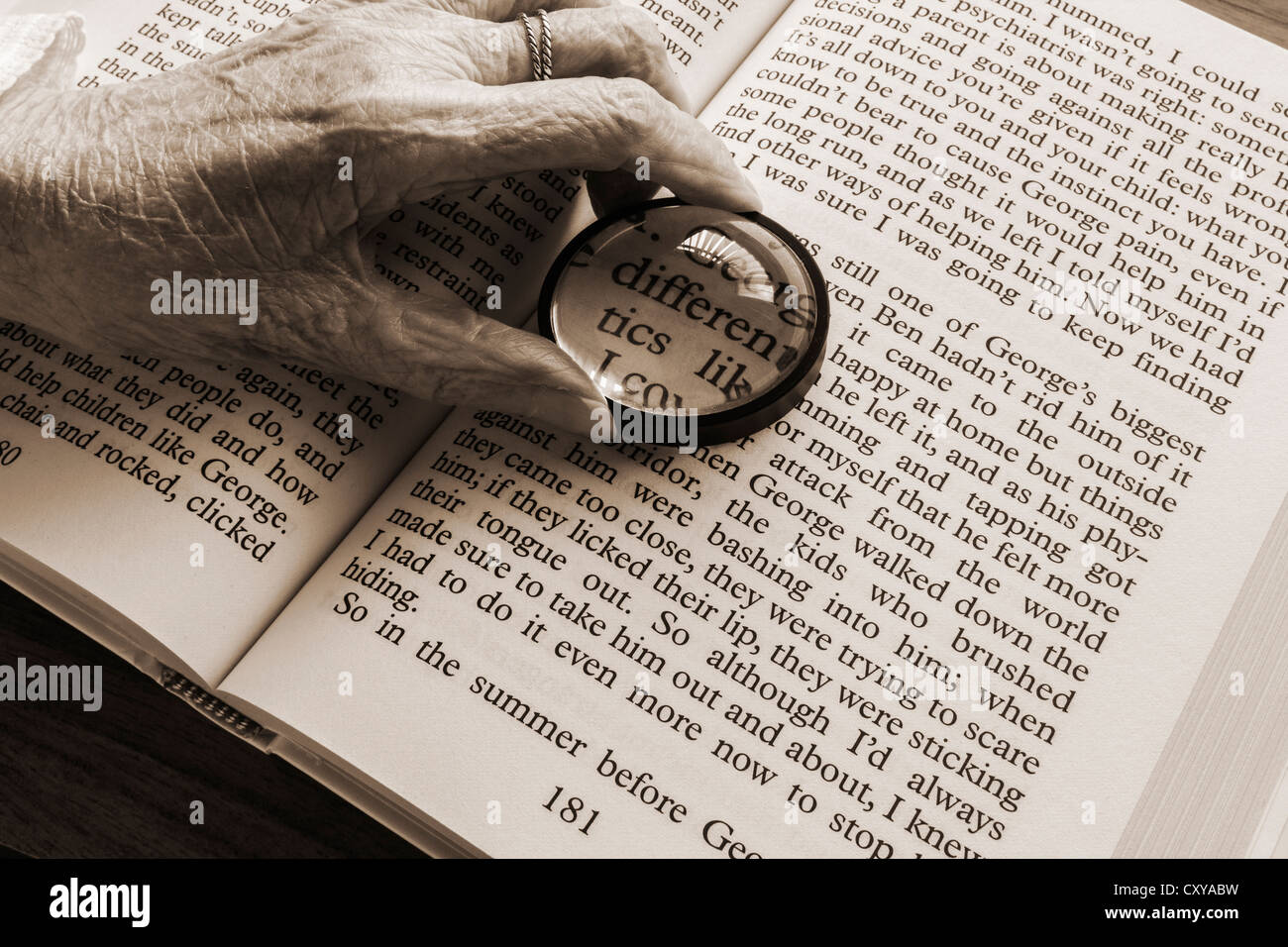 Elderly Lady With Impaired Vision Using Magnifying Loupe To Read Large Print Book Stock Photo 