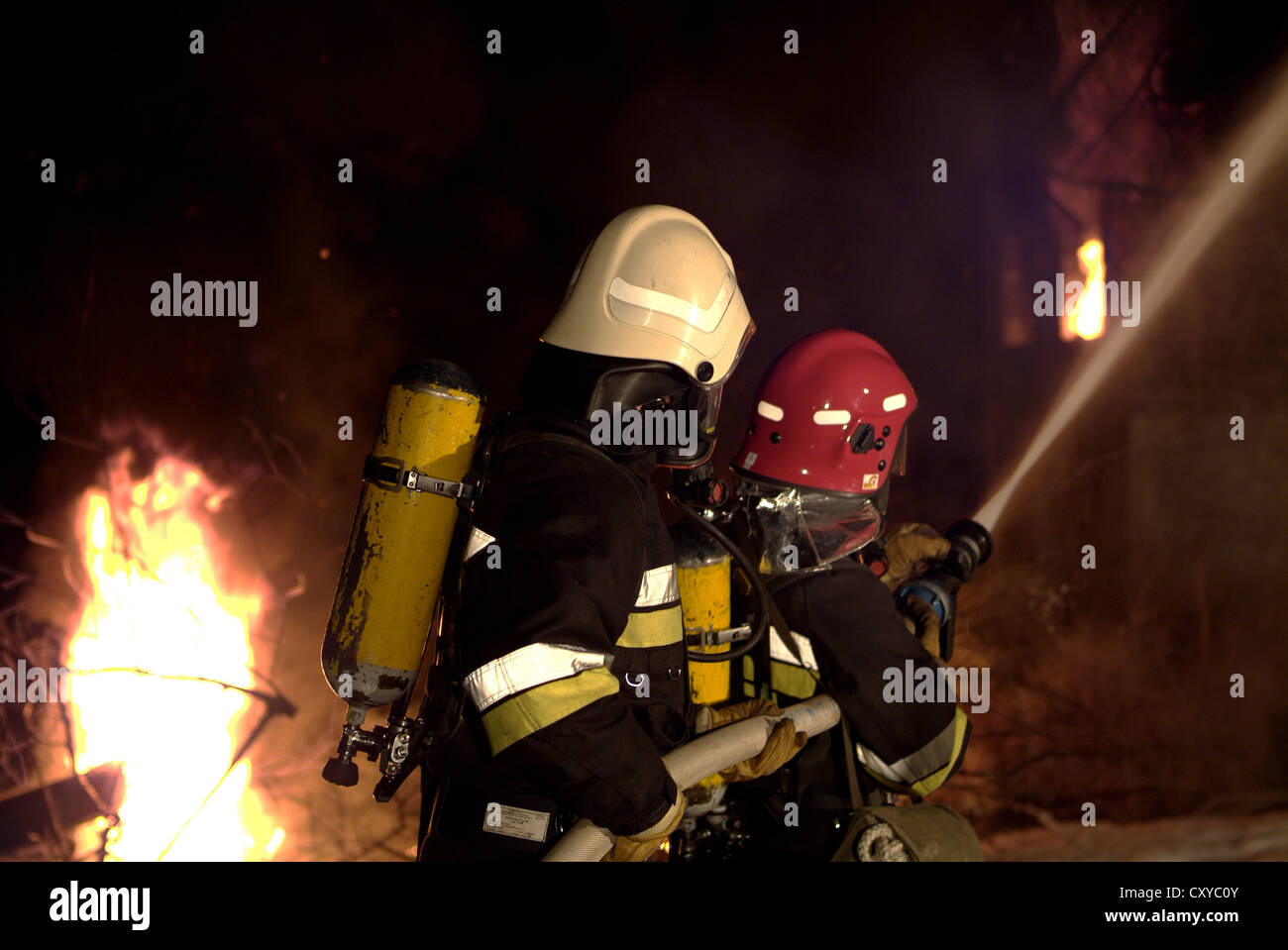 Firefighters extinguishing a fire, seen from behind Stock Photo - Alamy