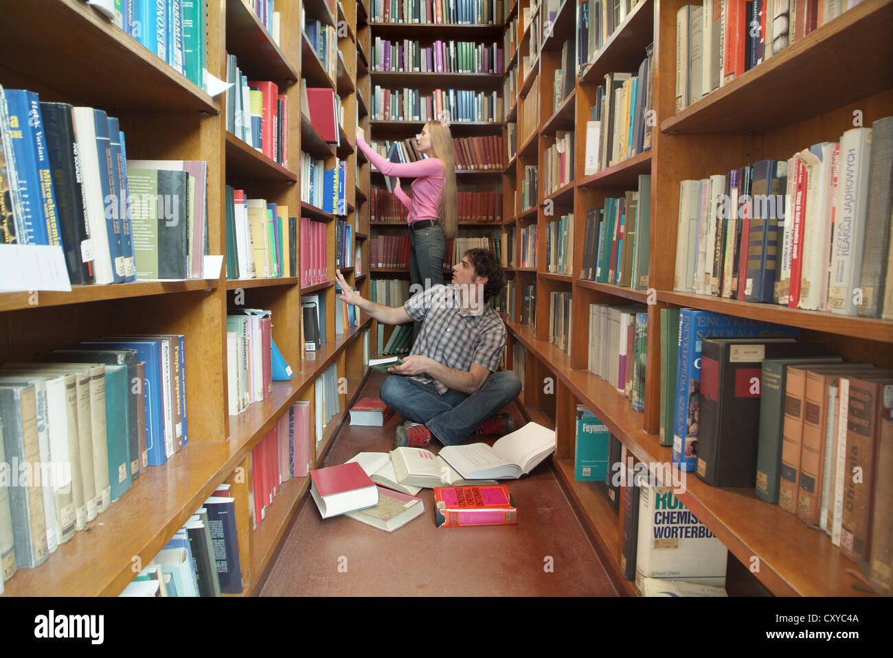 Students between bookshelves in a university library Stock Photo - Alamy