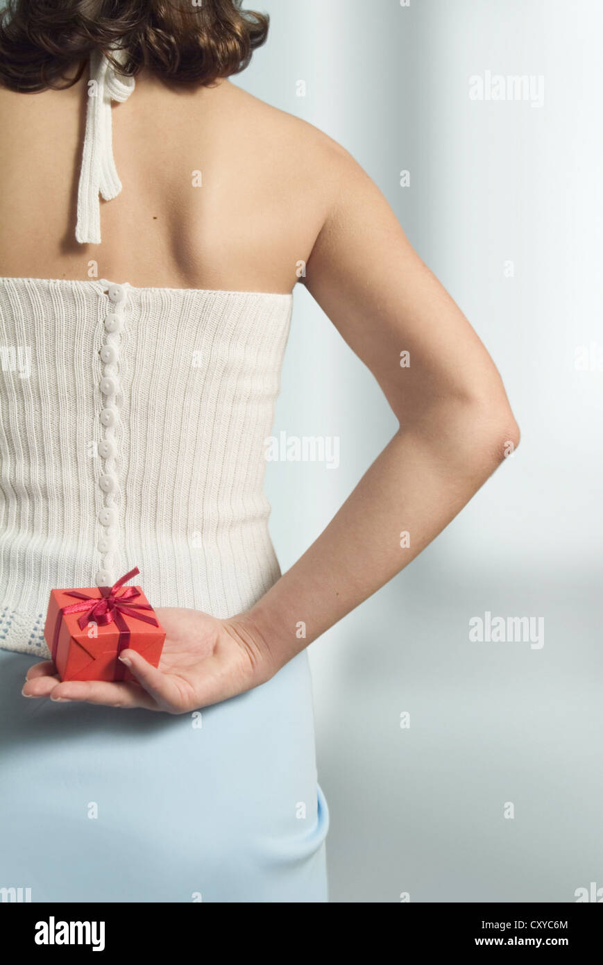 Woman hiding gift behind her back Stock Photo - Alamy