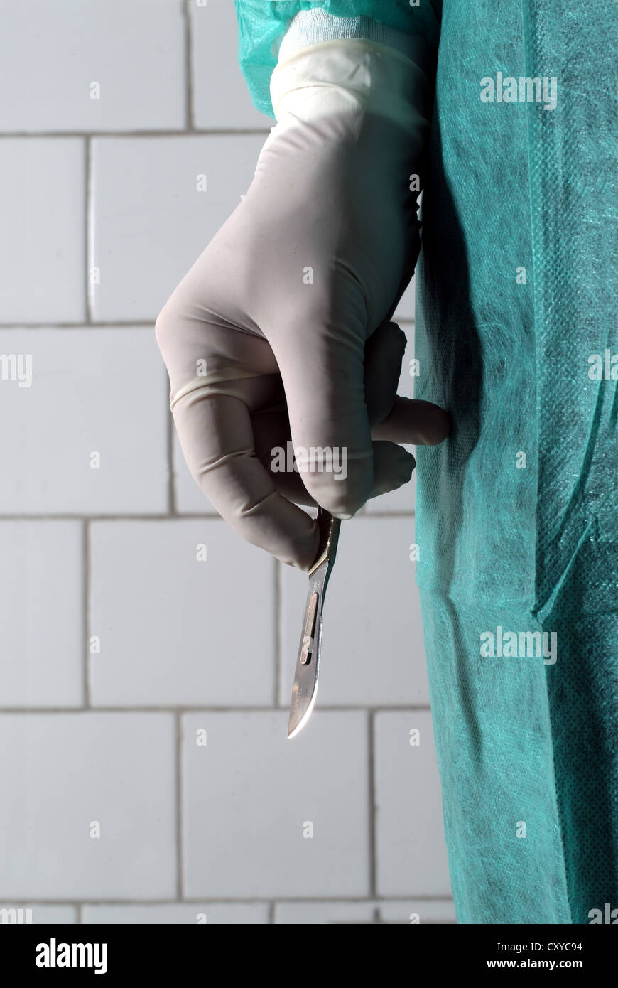 Surgeon wearing surgical clothes, detail of a hand holding a scalpel ...