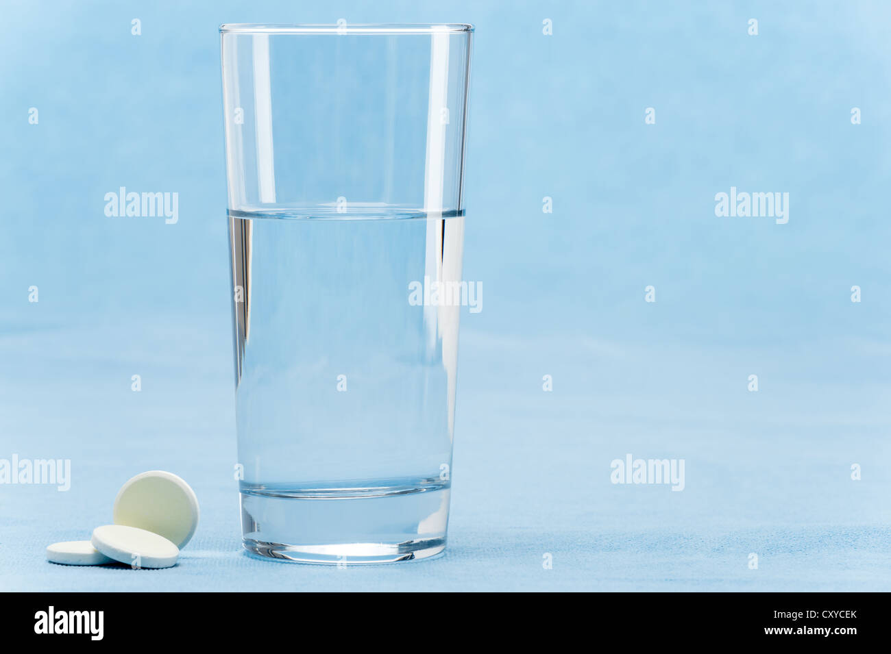 Soluble tablet throw in water glass on blue background Stock Photo - Alamy