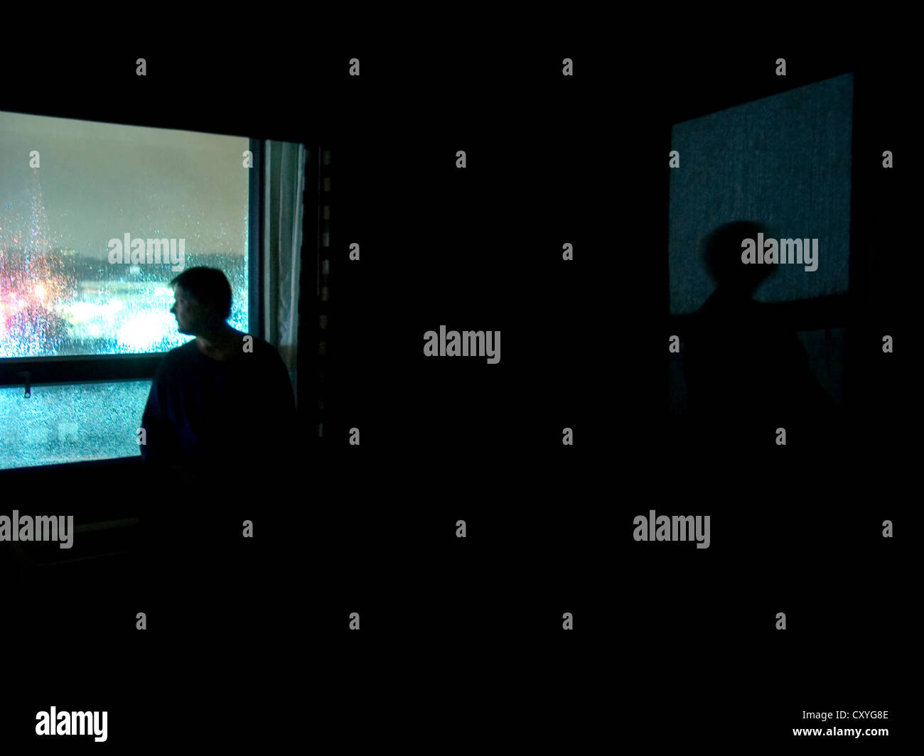 A figure standing in a dark room looking our of a window Stock Photo ...