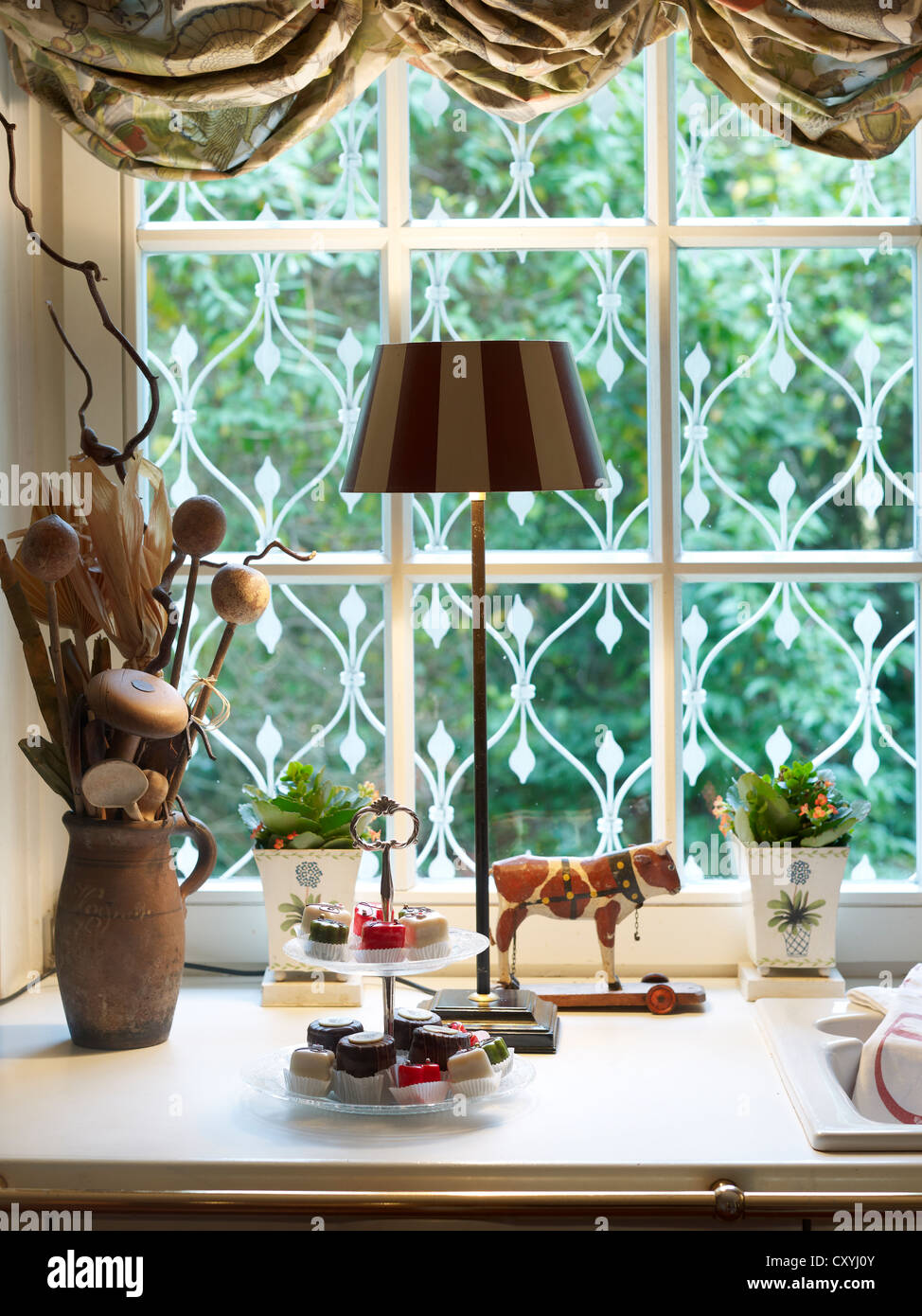 Still life, window with antique lamp and petit fours, stylish ...