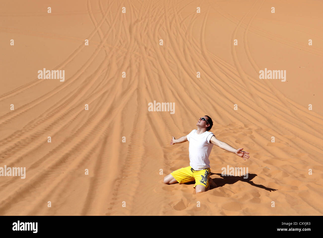 Man with outstretched arms in the desert, Coral Pink Sand Dunes State ...
