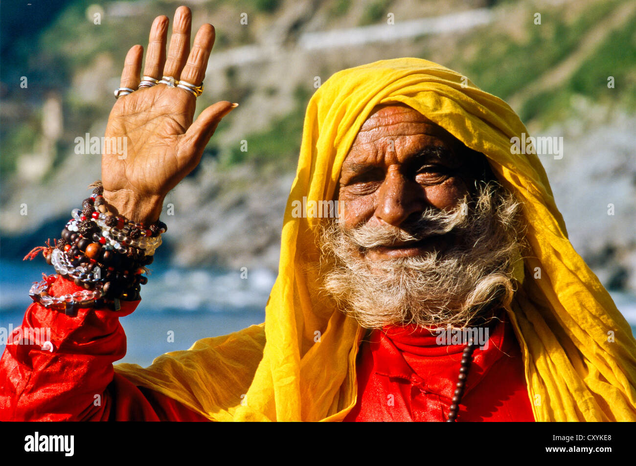 Sadhu, holy man, waving, at the confluence of the holy rivers Baghirati ...