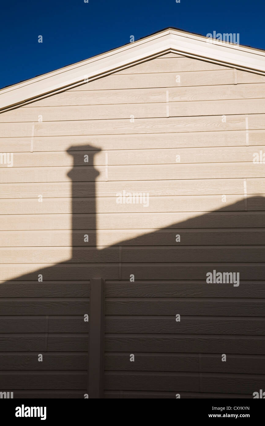 Roofline and chimney shadow on the exterior side wall of a residential ...