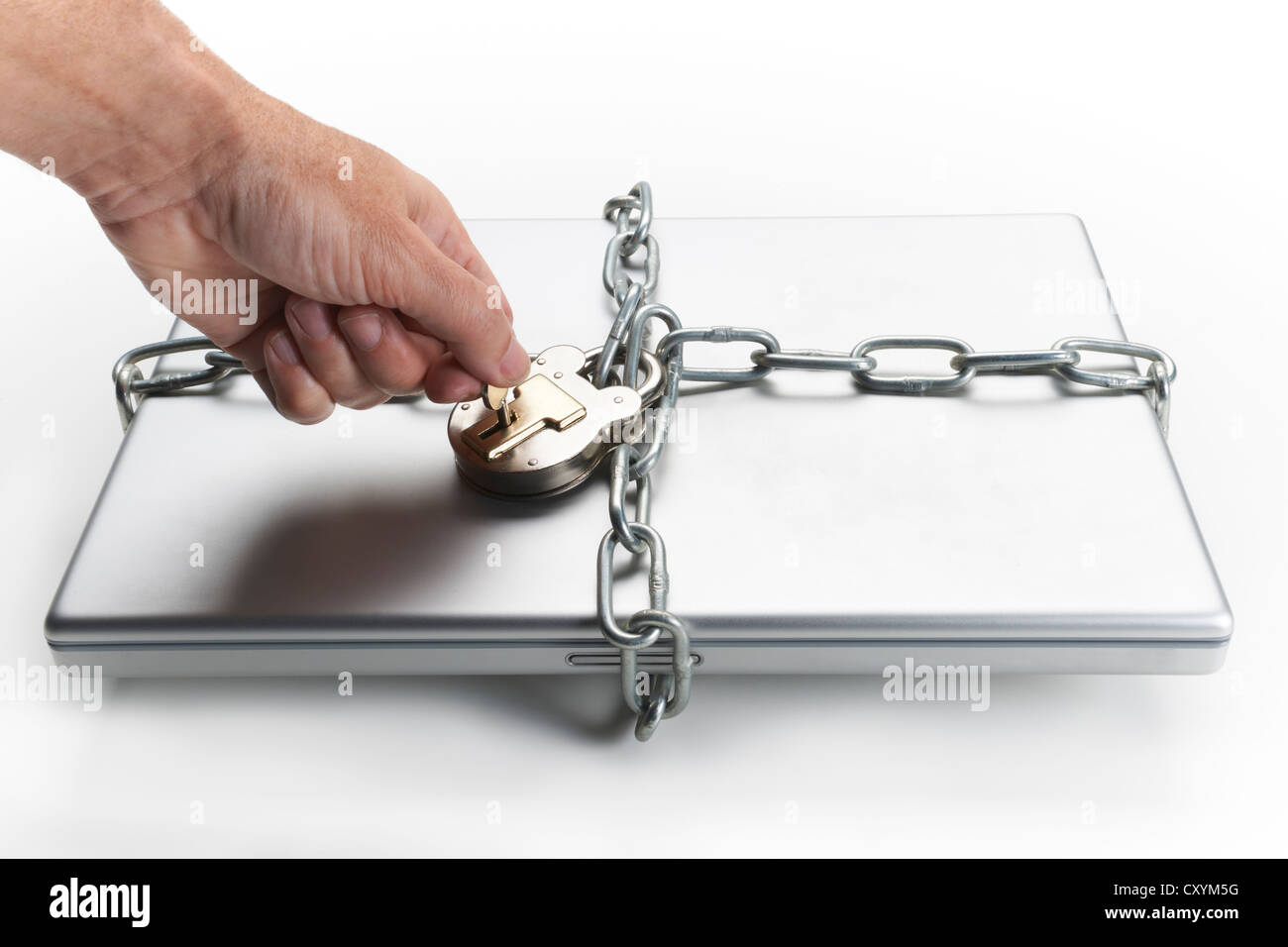 Mans hand placing key in padlock which is chained to closed laptop ...