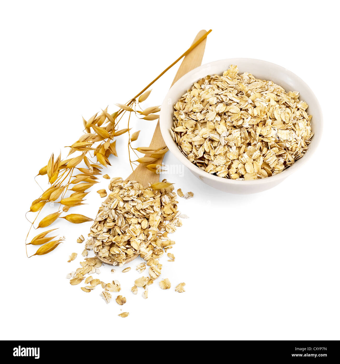Rolled oats in a wooden spoon and a white porcelain bowl, oat stalks ...
