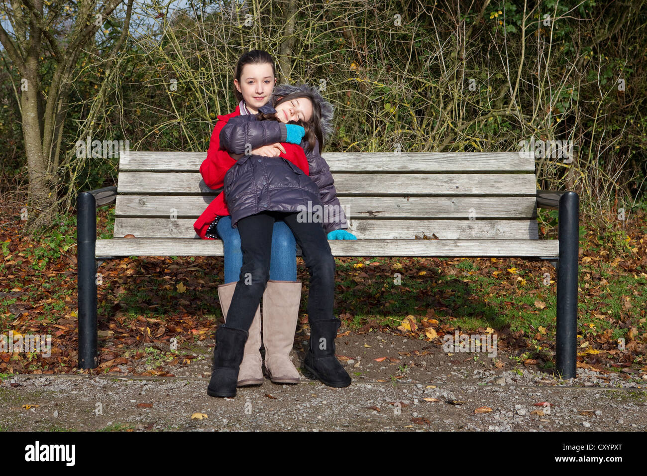 Two sisters cuddling on park bench Stock Photo - Alamy