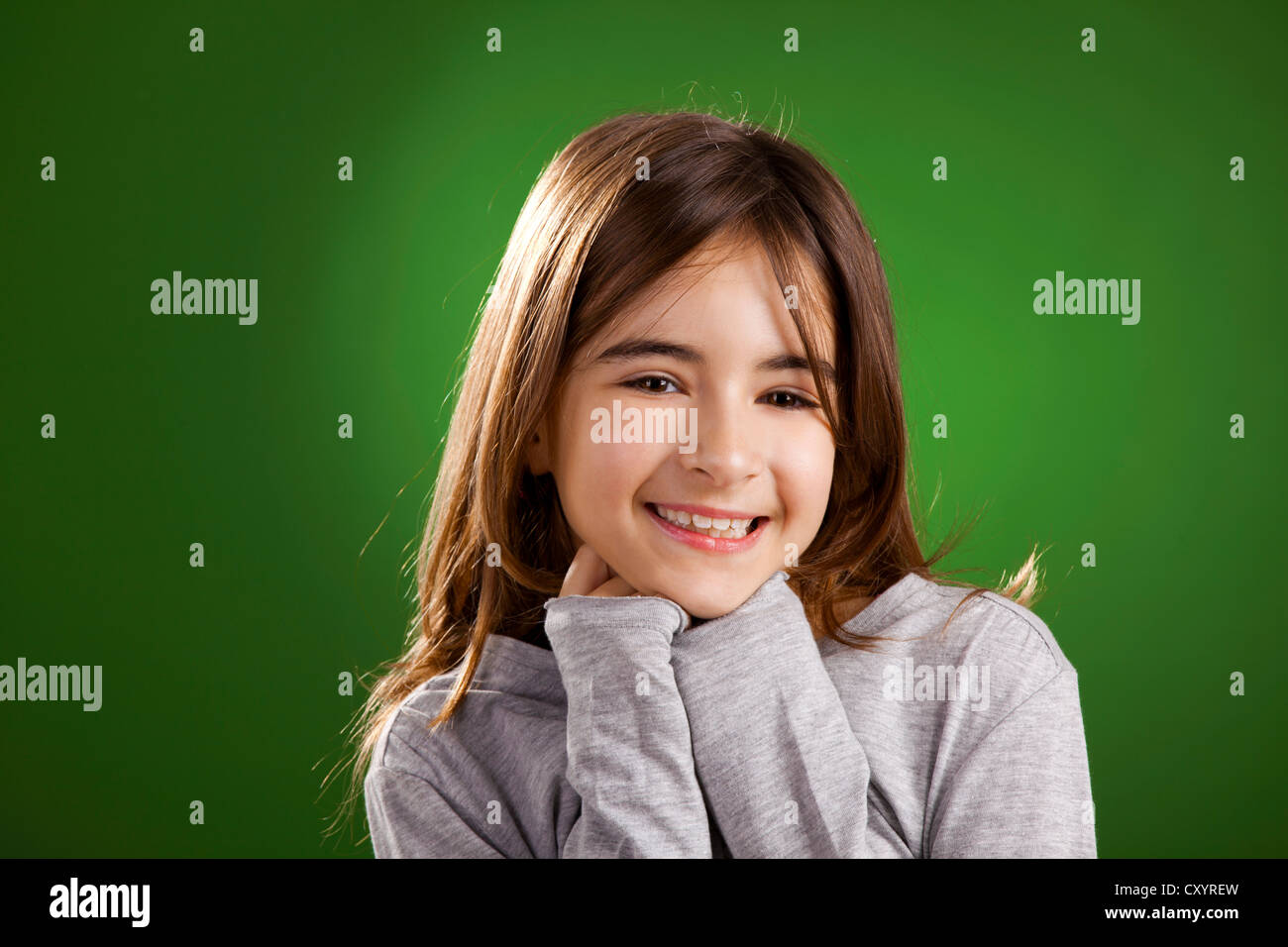 Beautiful child smiling into the camera, against a green background ...