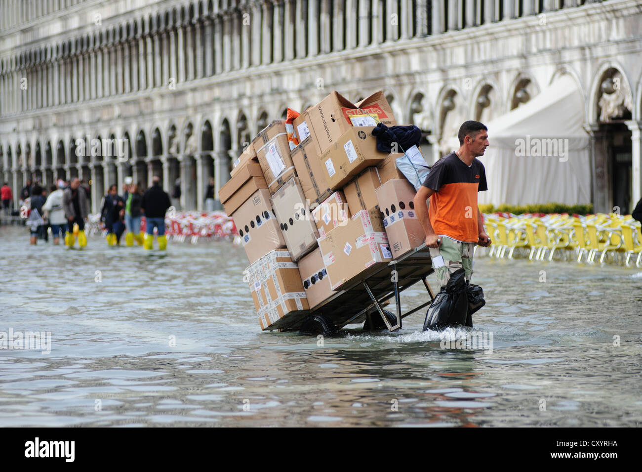 A local worker pushes a trolley full of boxes in a flooded St. Mark's ...