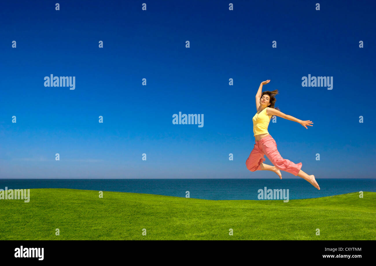 Beautiful woman jumping on a green field Stock Photo - Alamy