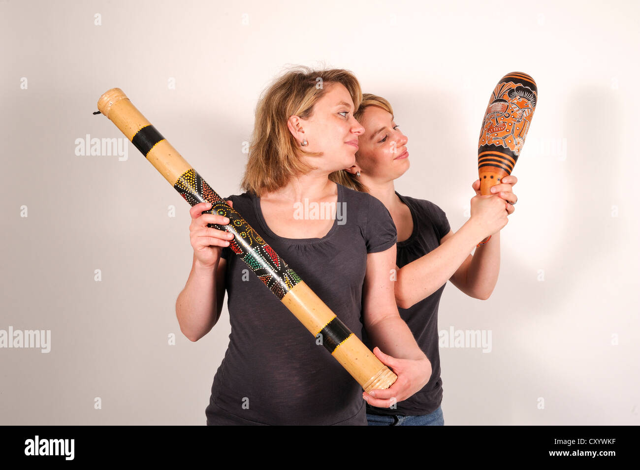 Twin sisters holding musical instruments, rattles Stock Photo - Alamy
