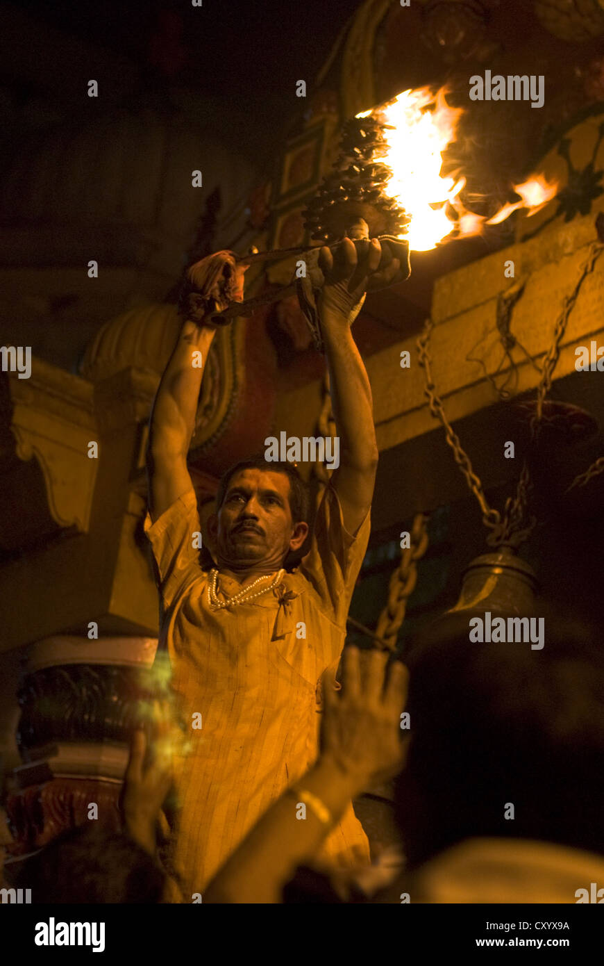 A Hindu Pujari (priest) raises flaming offerings from worshippers at ...