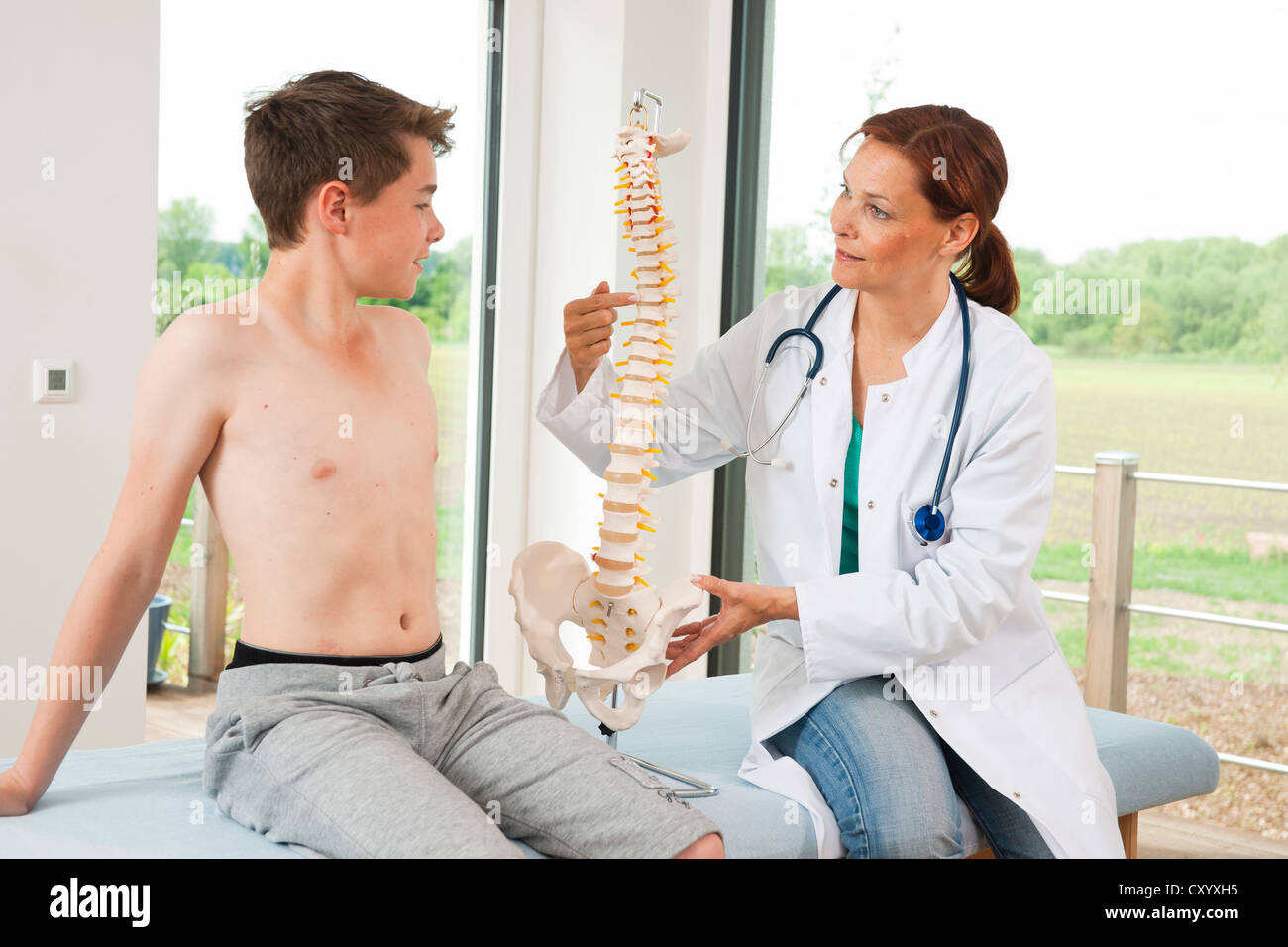 Orthopedic surgeon explaining a model of the spine to a teenage boy ...