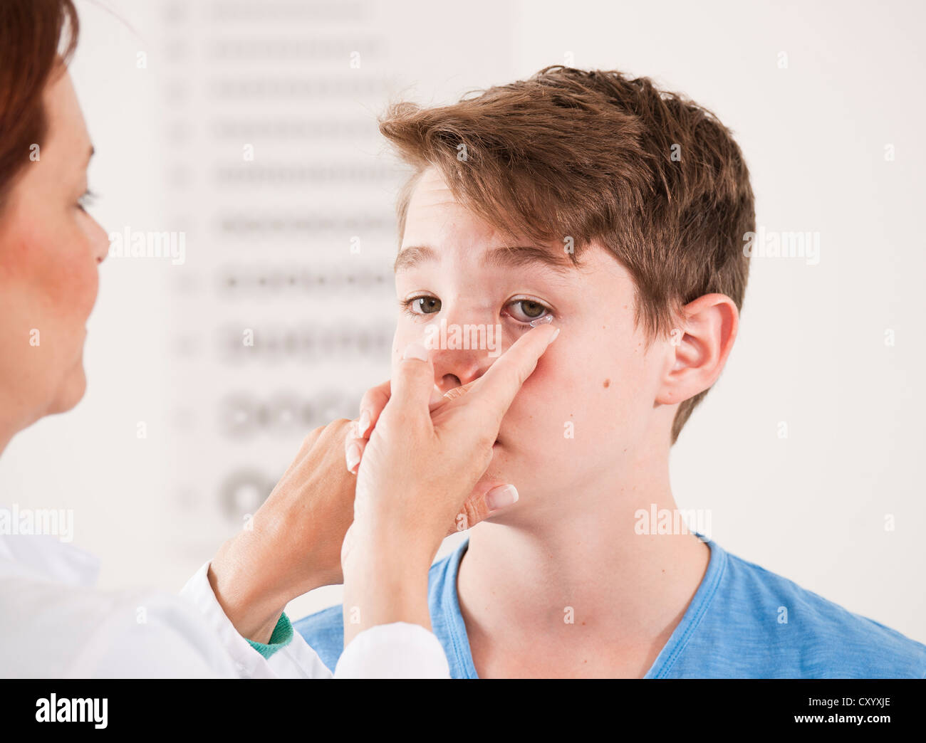 Ophthalmologist explaining the use of contact lenses to a teenage boy ...