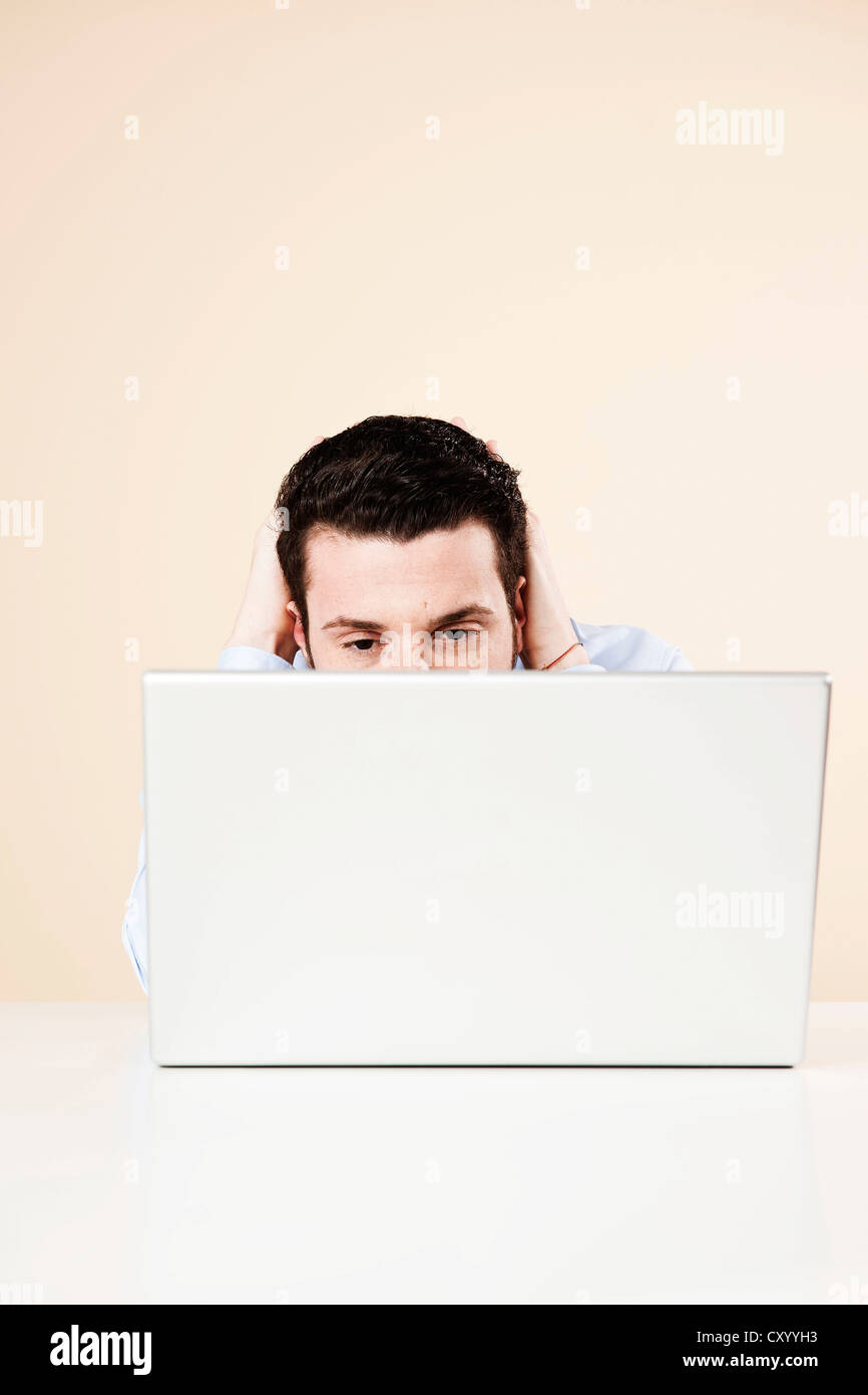 Young main sitting in front of his laptop computer, in despair Stock ...