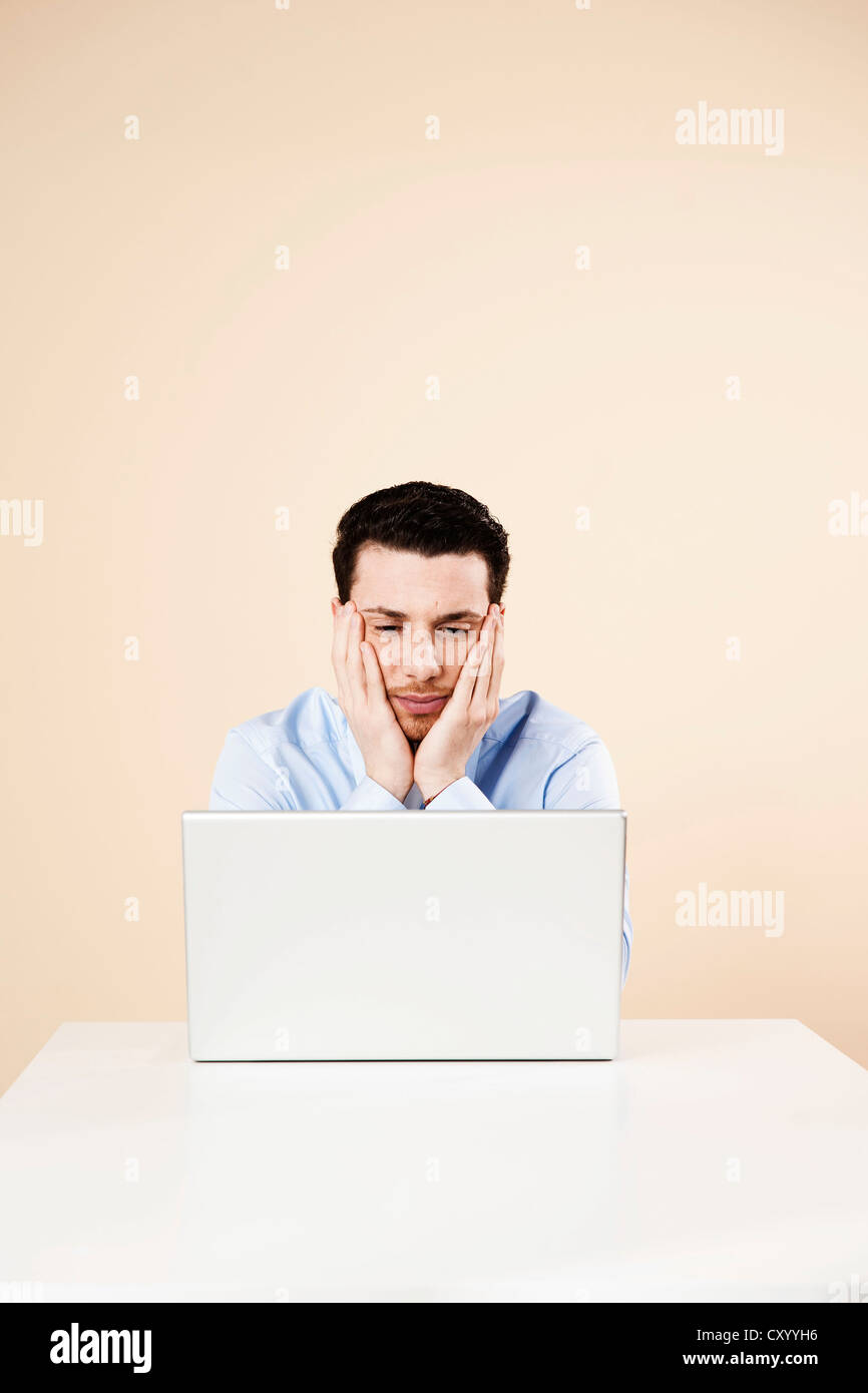 Young man sitting in front of his laptop computer, thoughtful Stock ...
