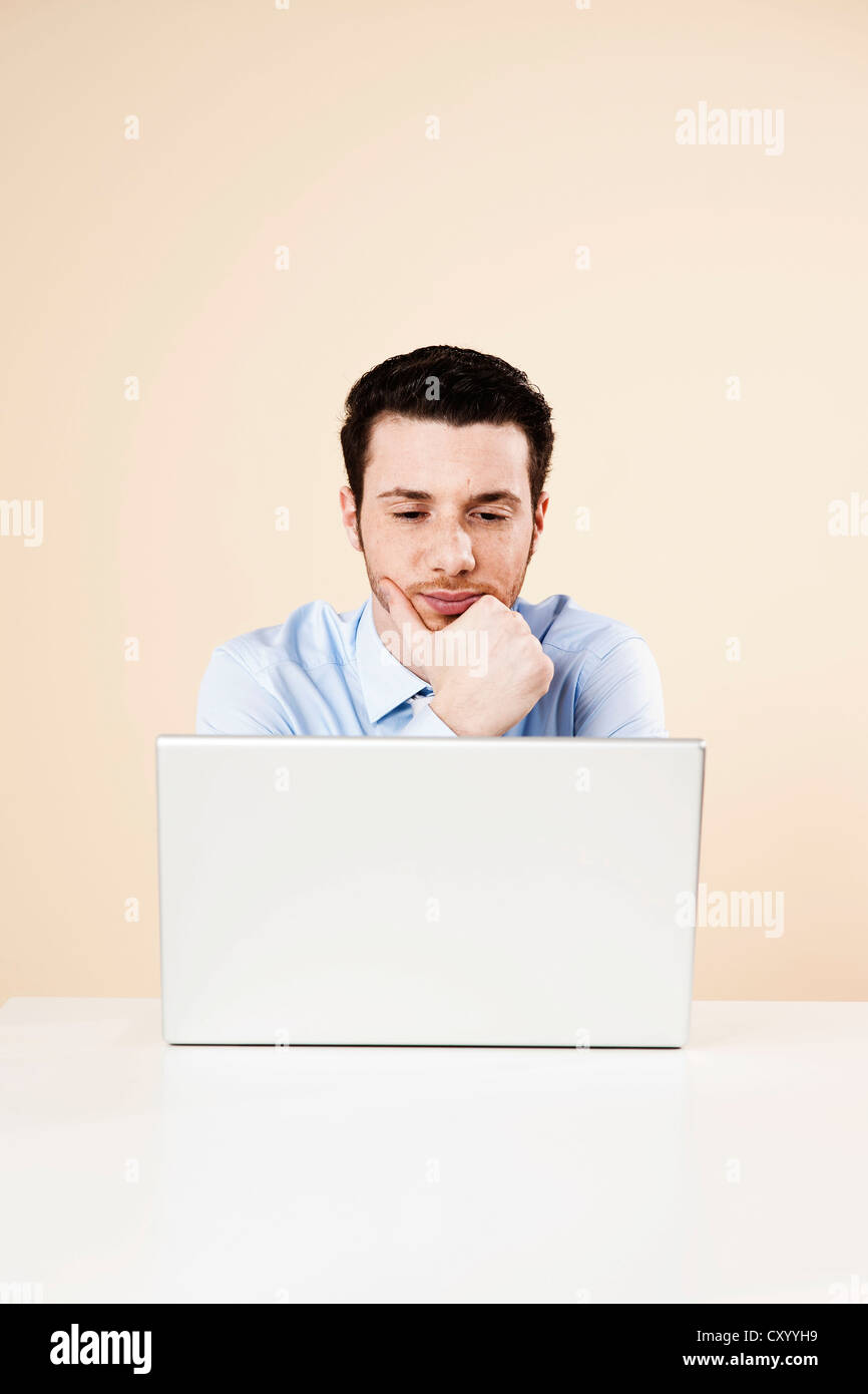 Young man sitting in front of his laptop computer, thoughtful Stock ...