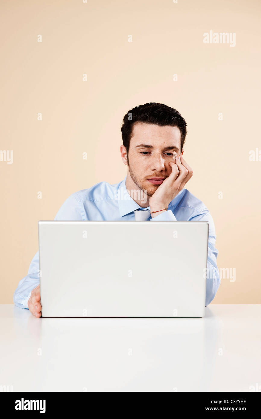Young man sitting in front of his laptop computer, thoughtful Stock ...
