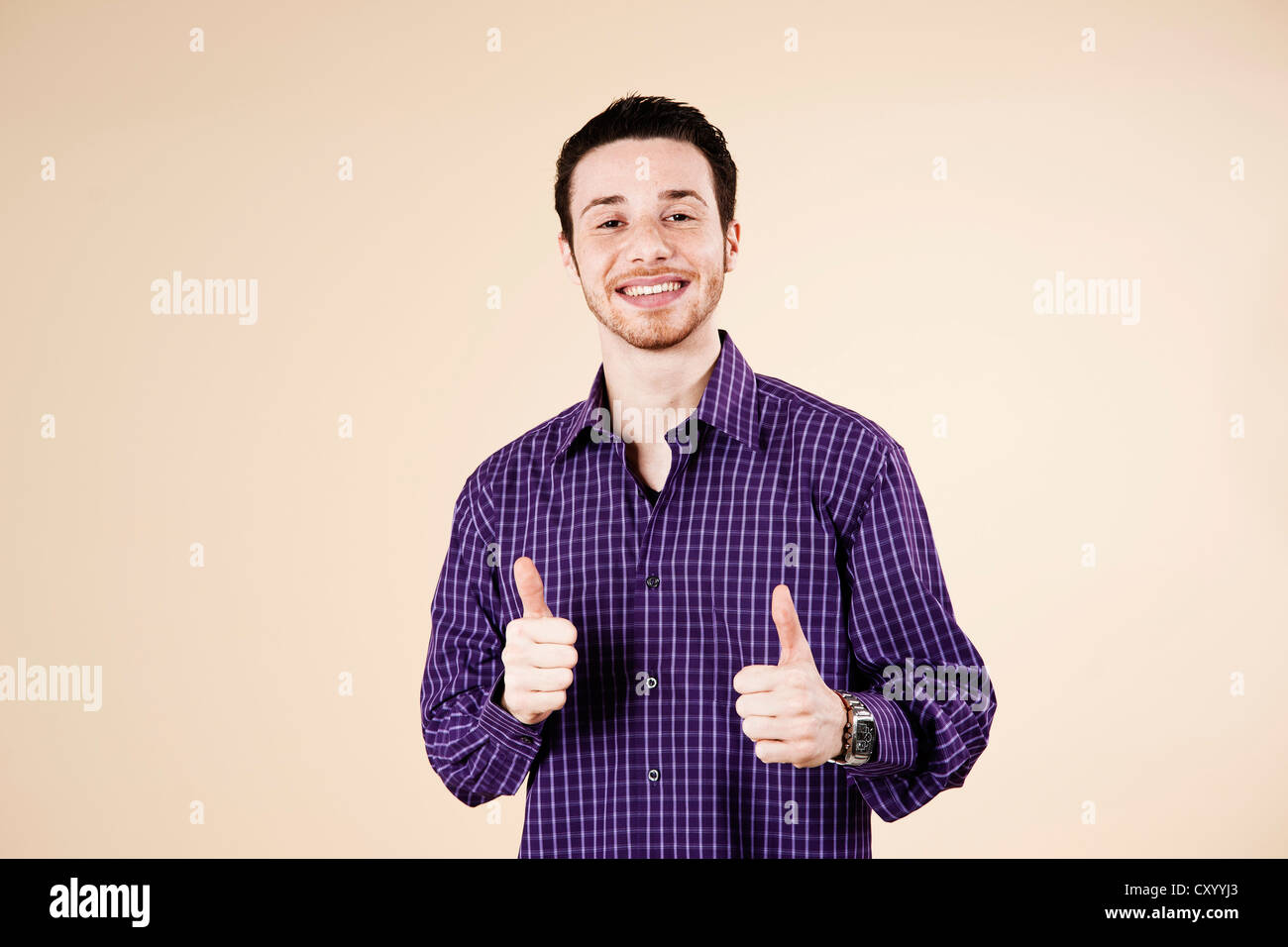 Young man making a thumbs-up gesture with both hands Stock Photo - Alamy
