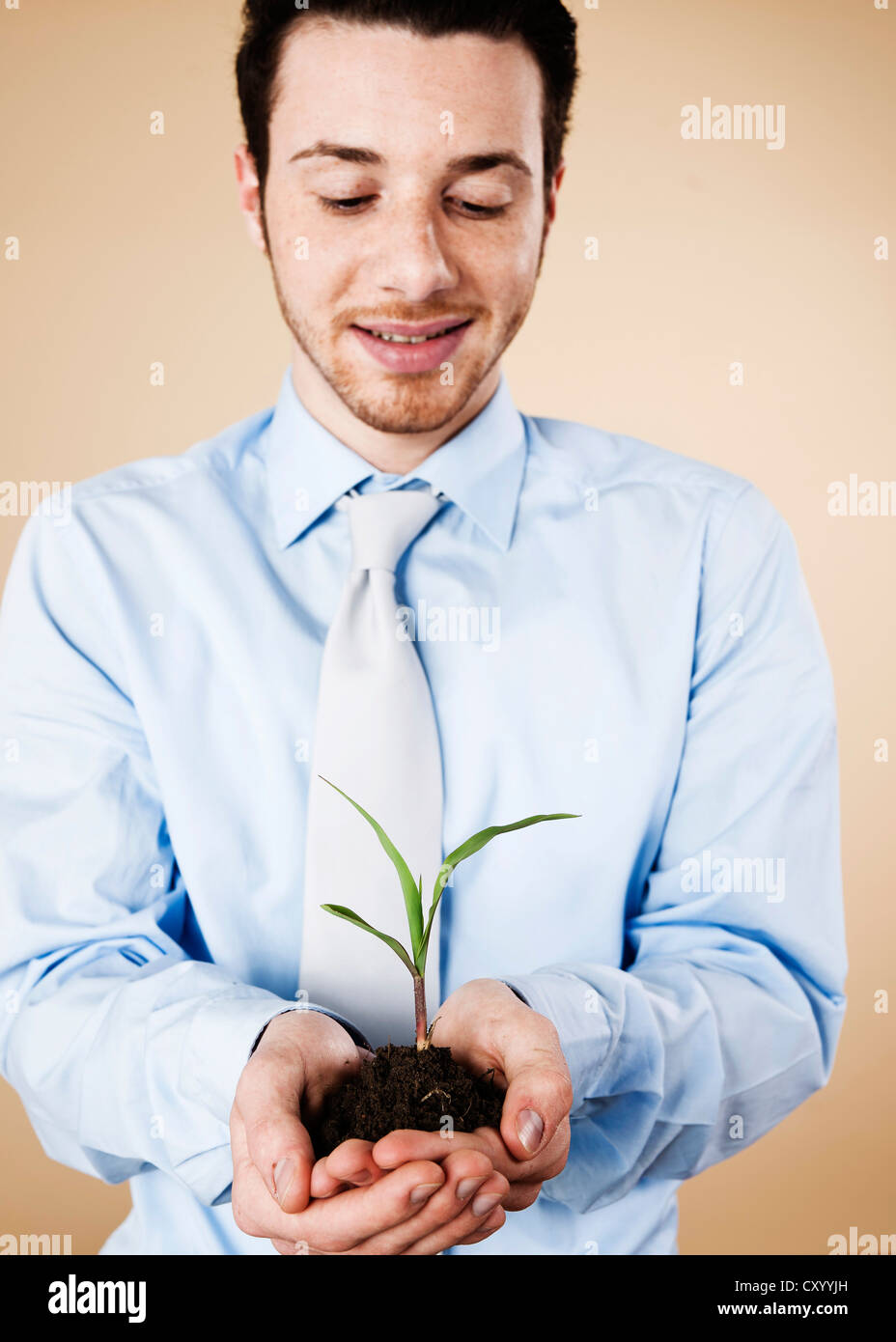 Smiling young manager holding a plant in his hands Stock Photo - Alamy